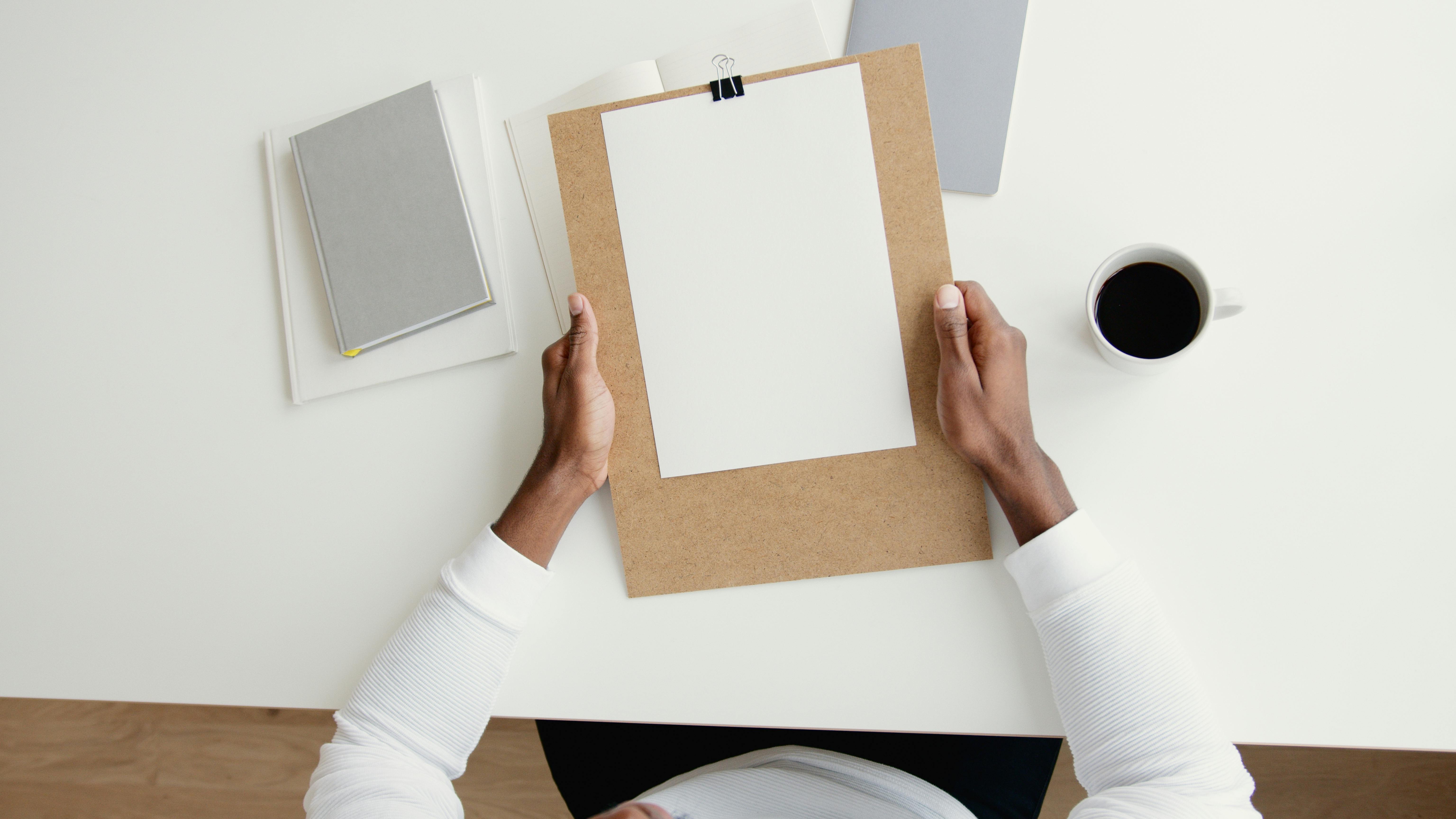 Person Holding A Clipboard With White Paper · Free Stock Photo