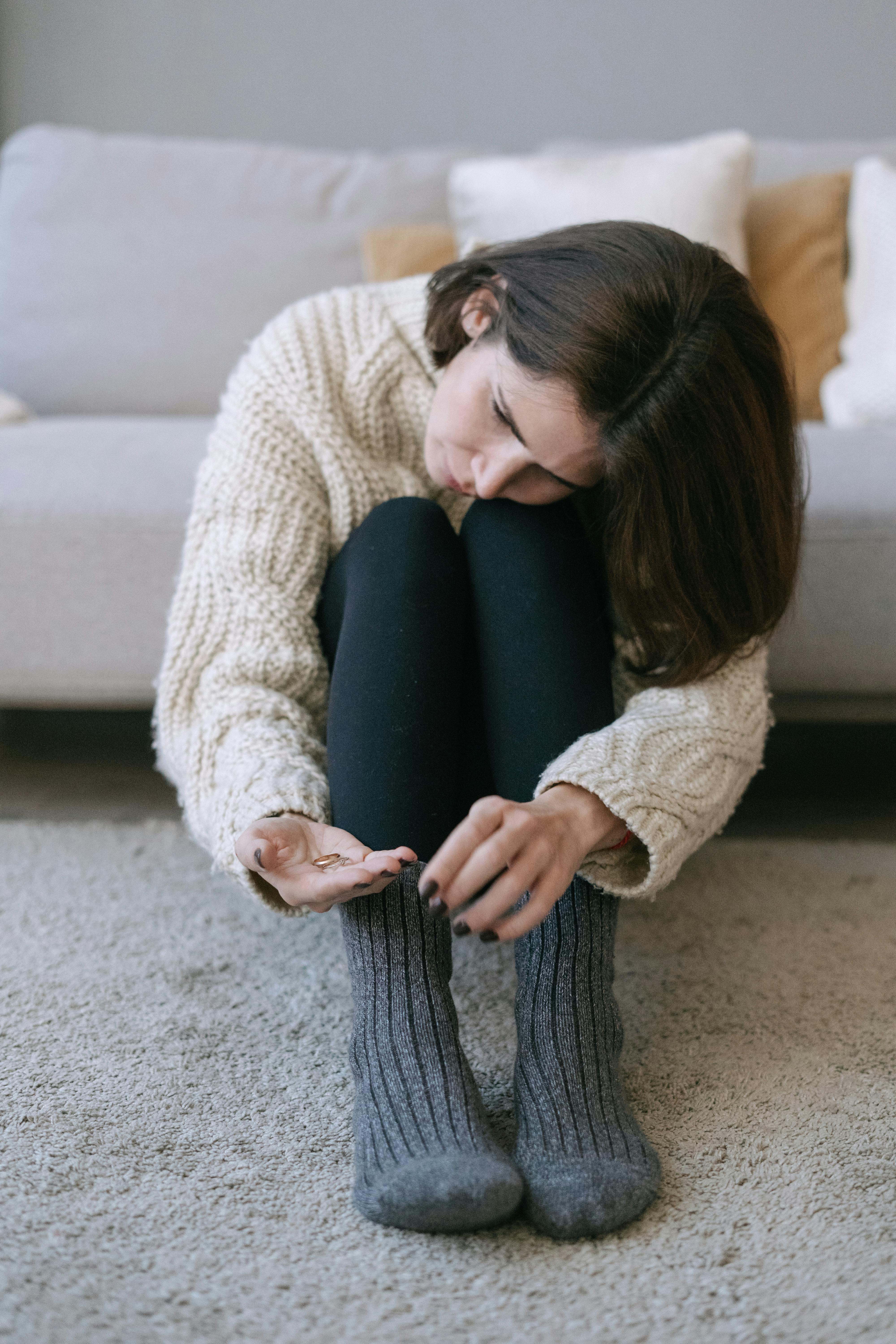 Woman Sitting on Carpet Near Sofa Holding a Ring · Free Stock Photo