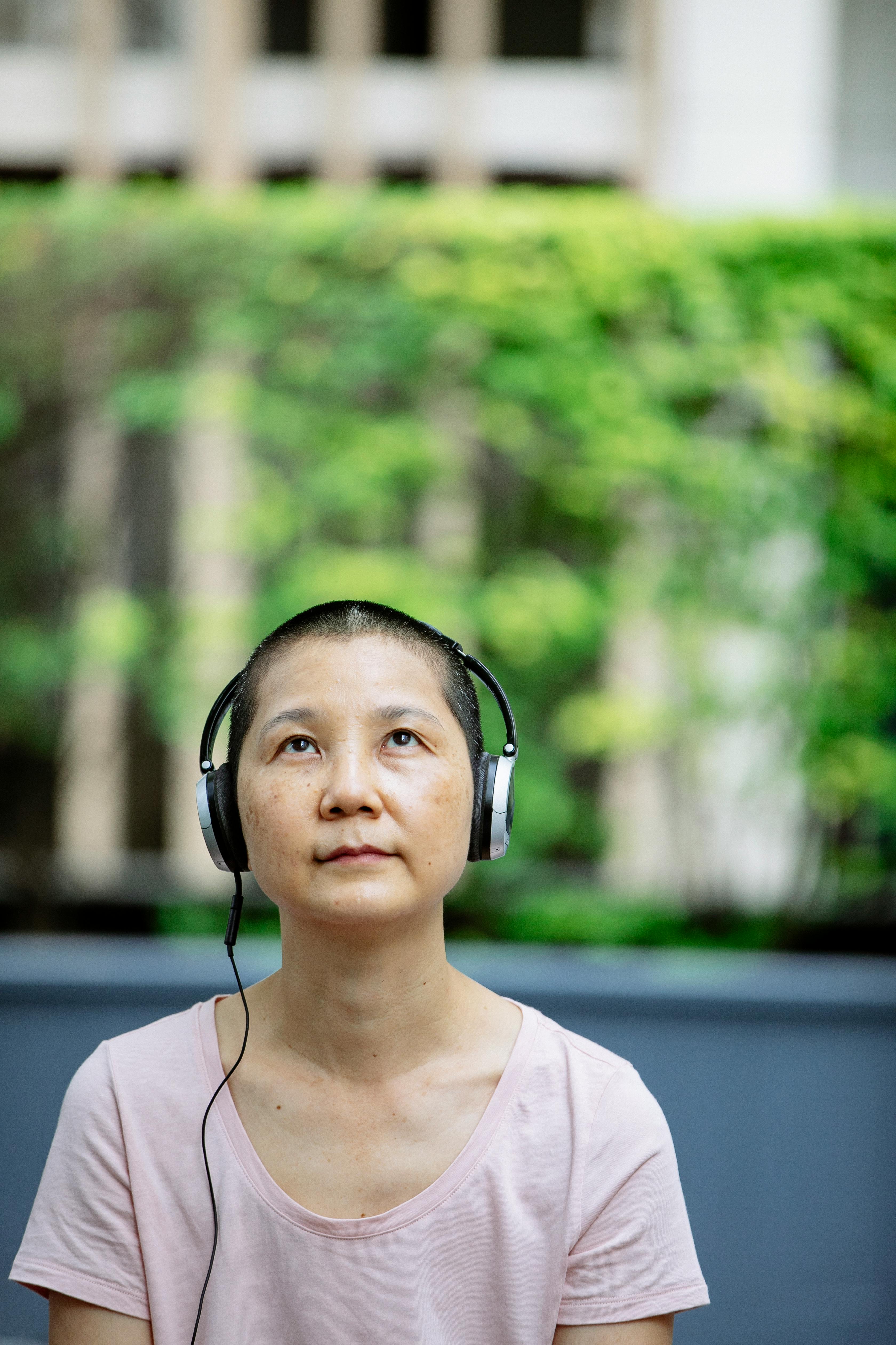 Calm Asian woman enjoying music in headphone in park · Free Stock Photo