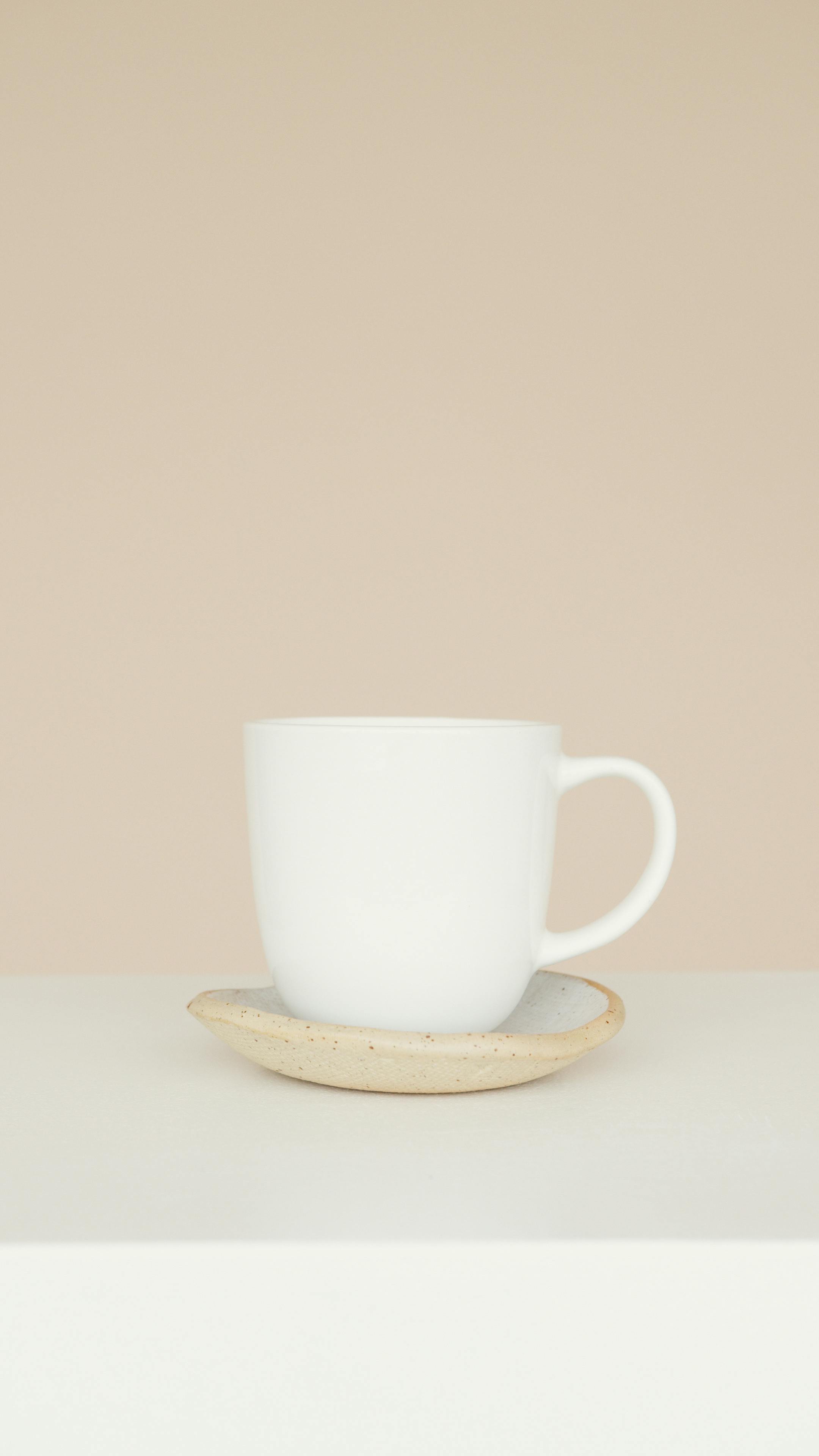 Coffee cup on table near green plant · Free Stock Photo