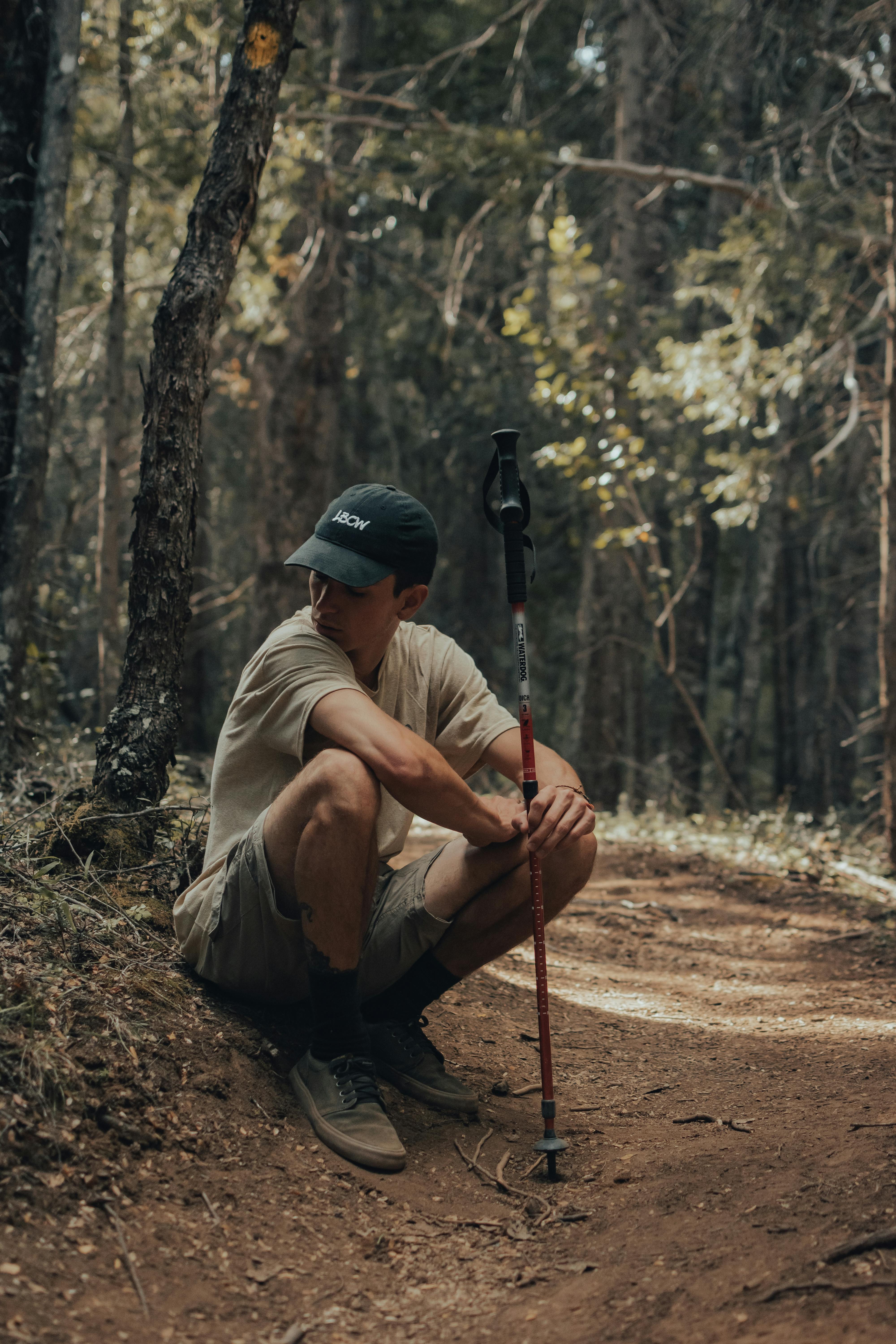Hiker sitting on ground in forest in sunny day · Free Stock Photo