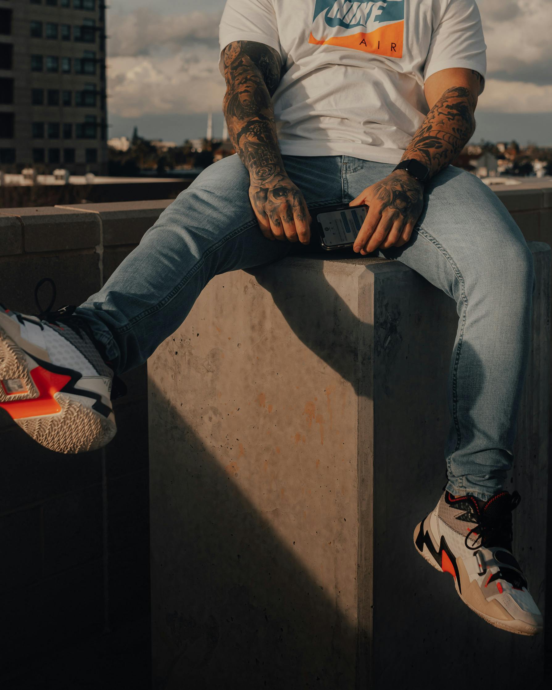 Crop faceless tattooed man sitting on stone parapet on street · Free ...
