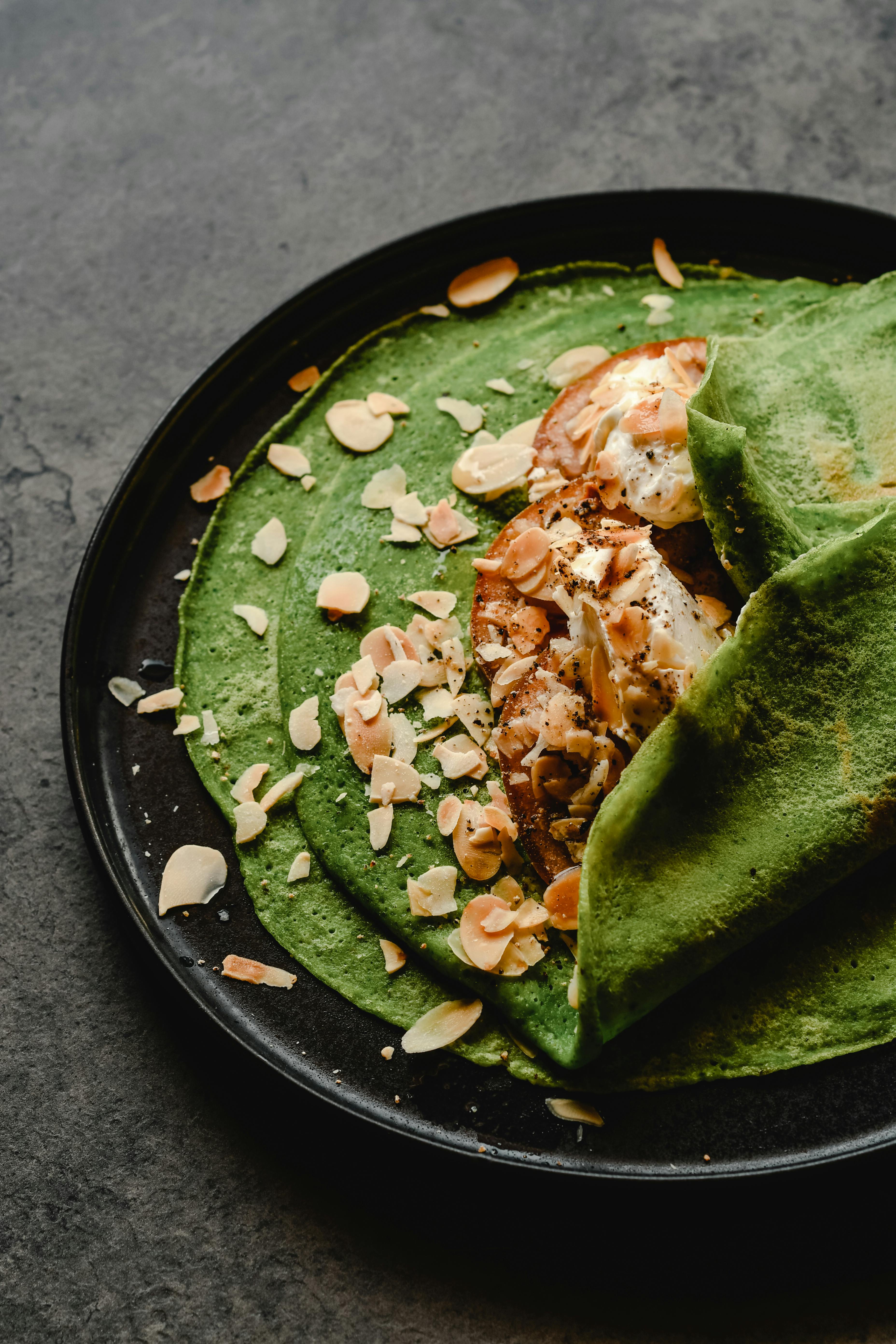 Green Crepes with Almond Flakes on Black Ceramic Plate · Free Stock Photo