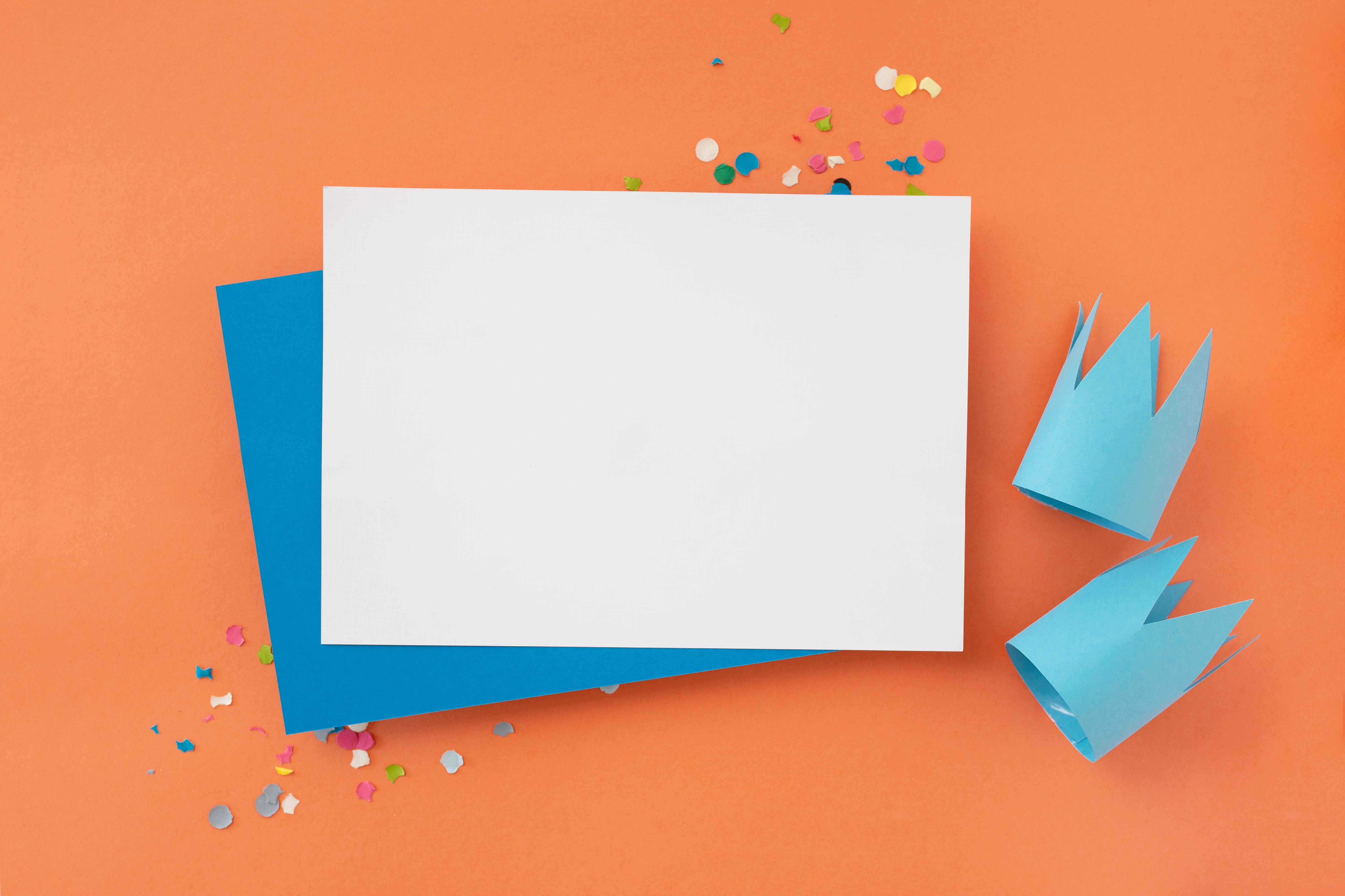 White and Blue Paper with Blue Paper Crowns and Confetti on Orange ...