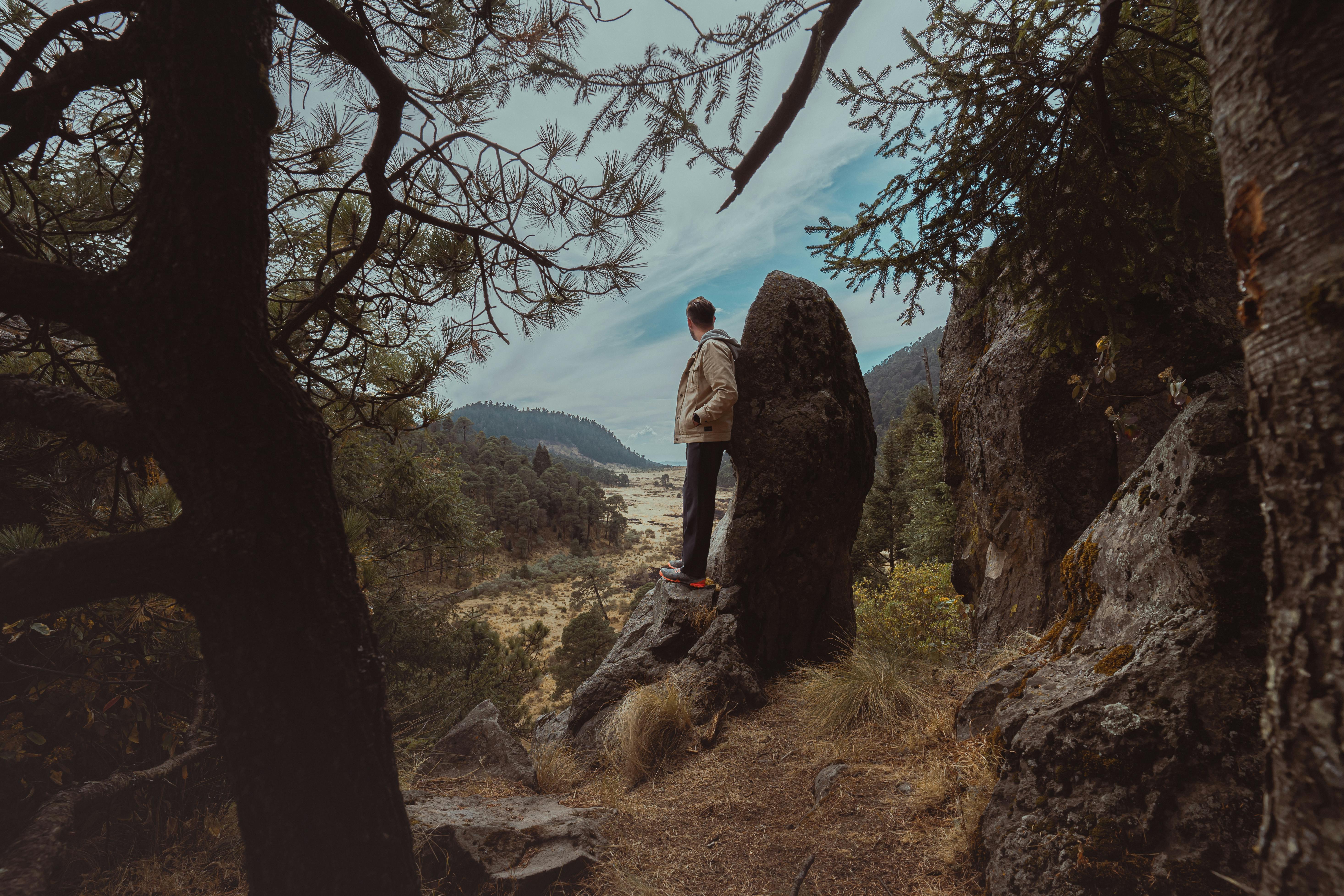 A Man Standing on big Rock while Looking at the Beautiful Scenery ...