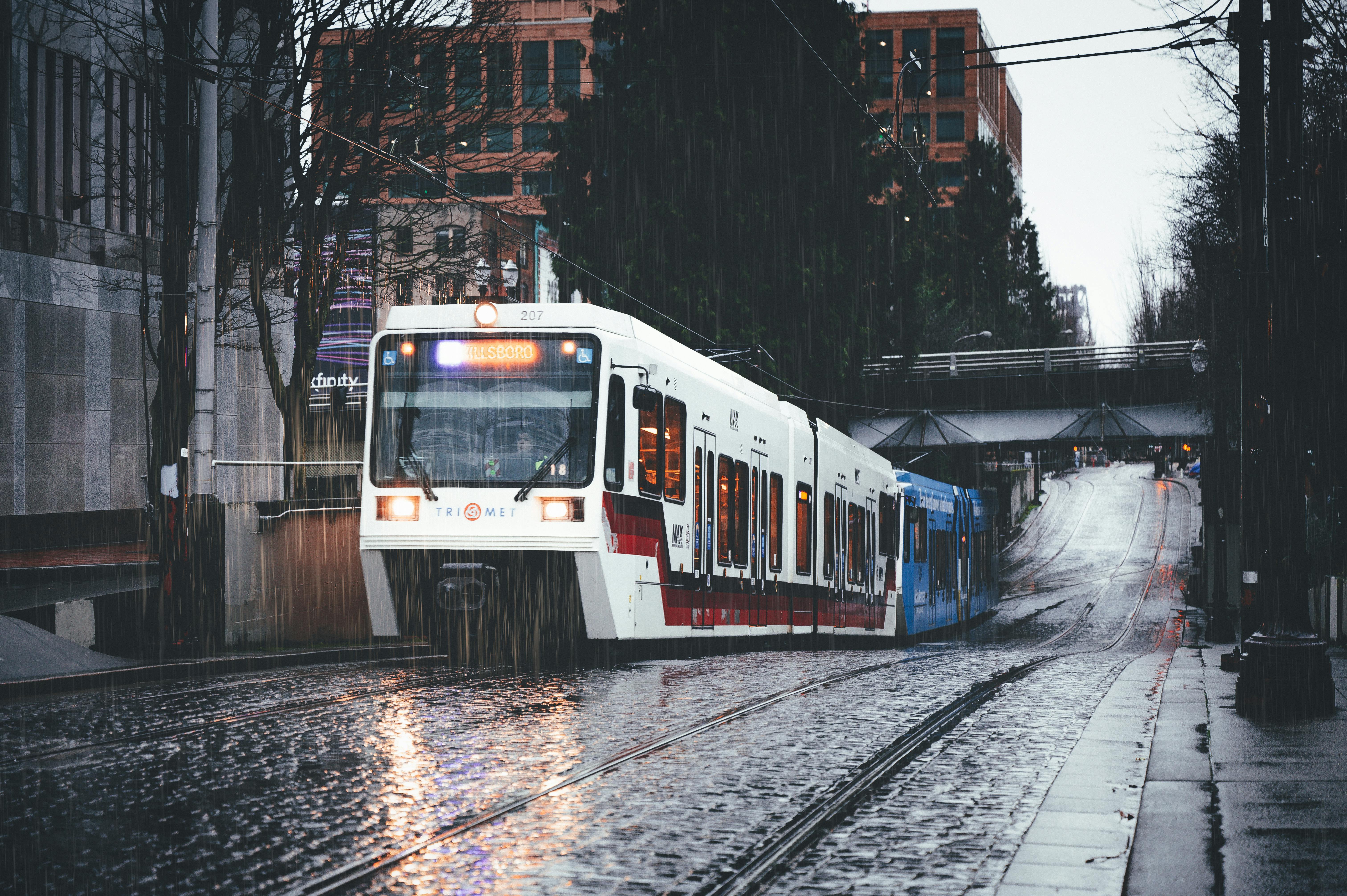 Tram riding along railroad under rain · Free Stock Photo