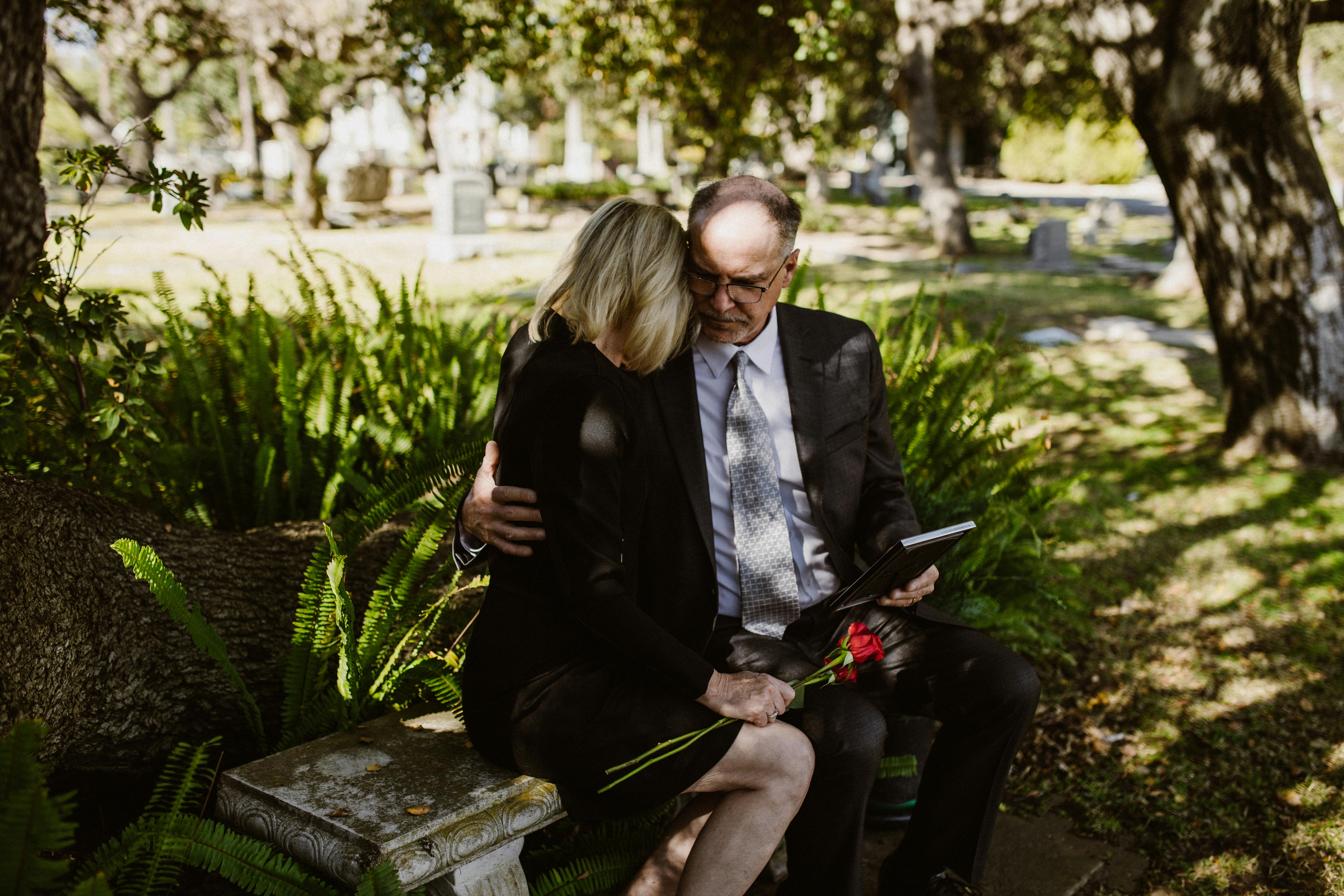 A Couple Sitting on Concrete Bench while Mourning · Free Stock Photo