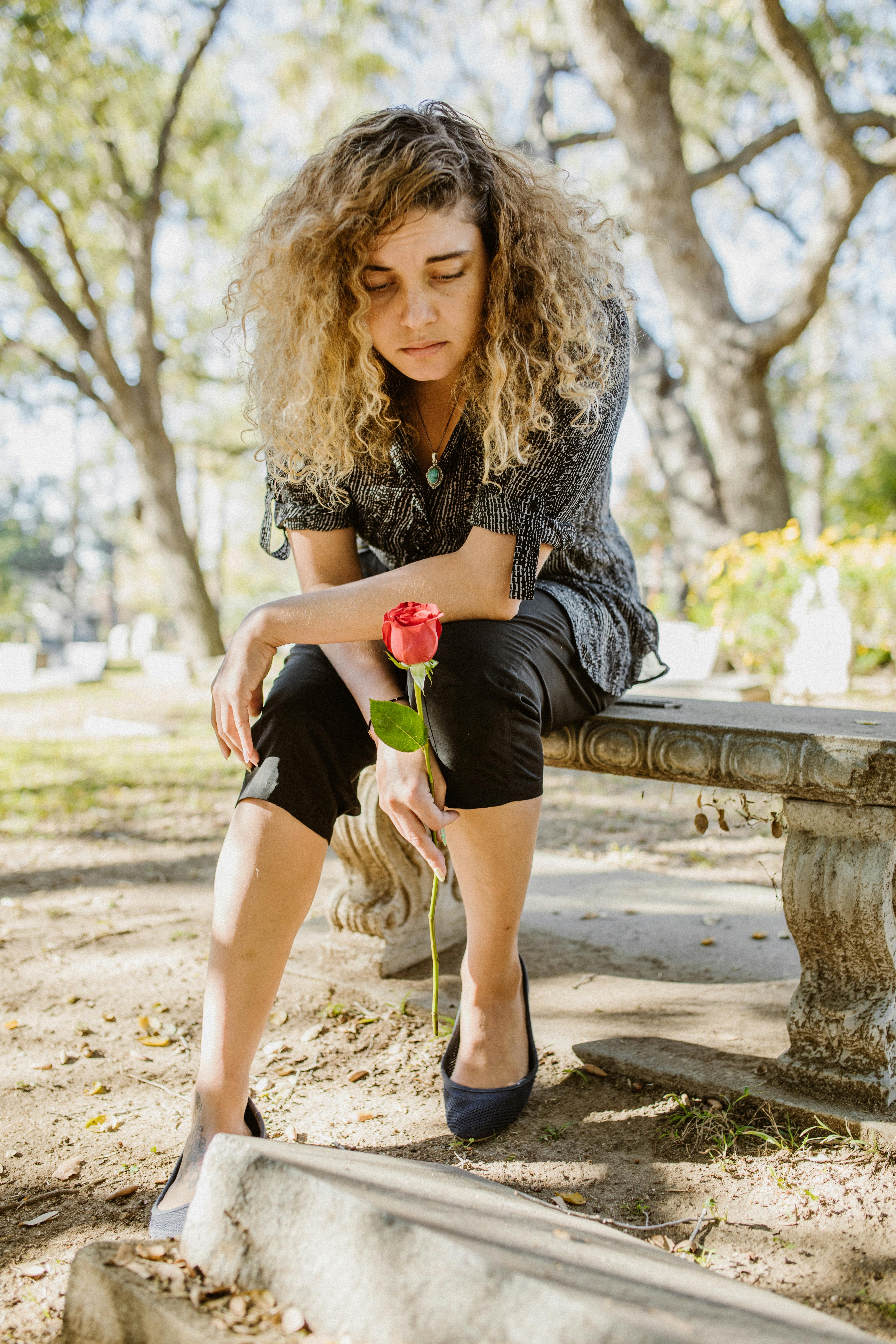A Grieving Woman Holding a Rose · Free Stock Photo