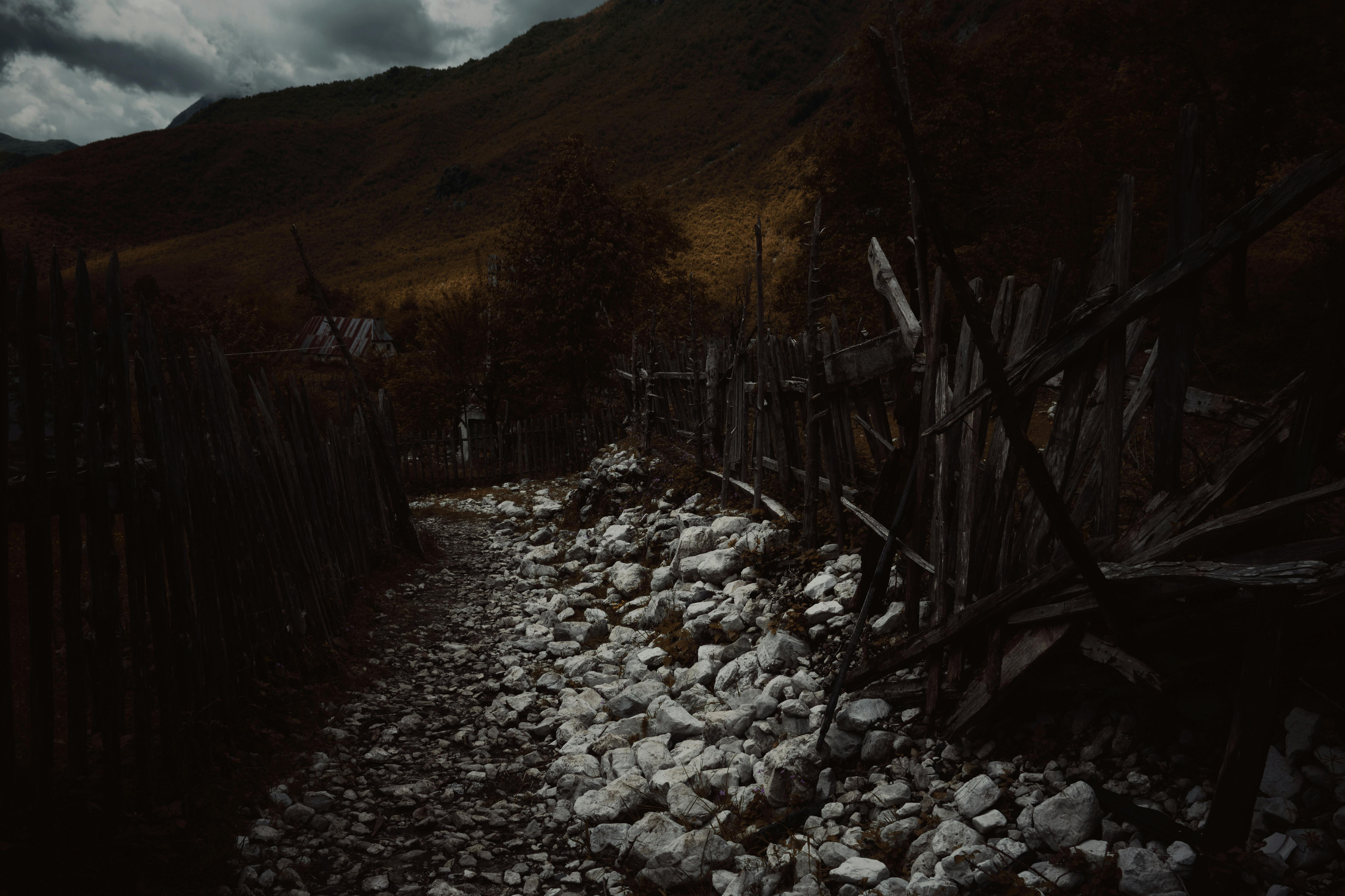 A Narrow Rocky Path Between a Ruined Wooden Fence · Free Stock Photo
