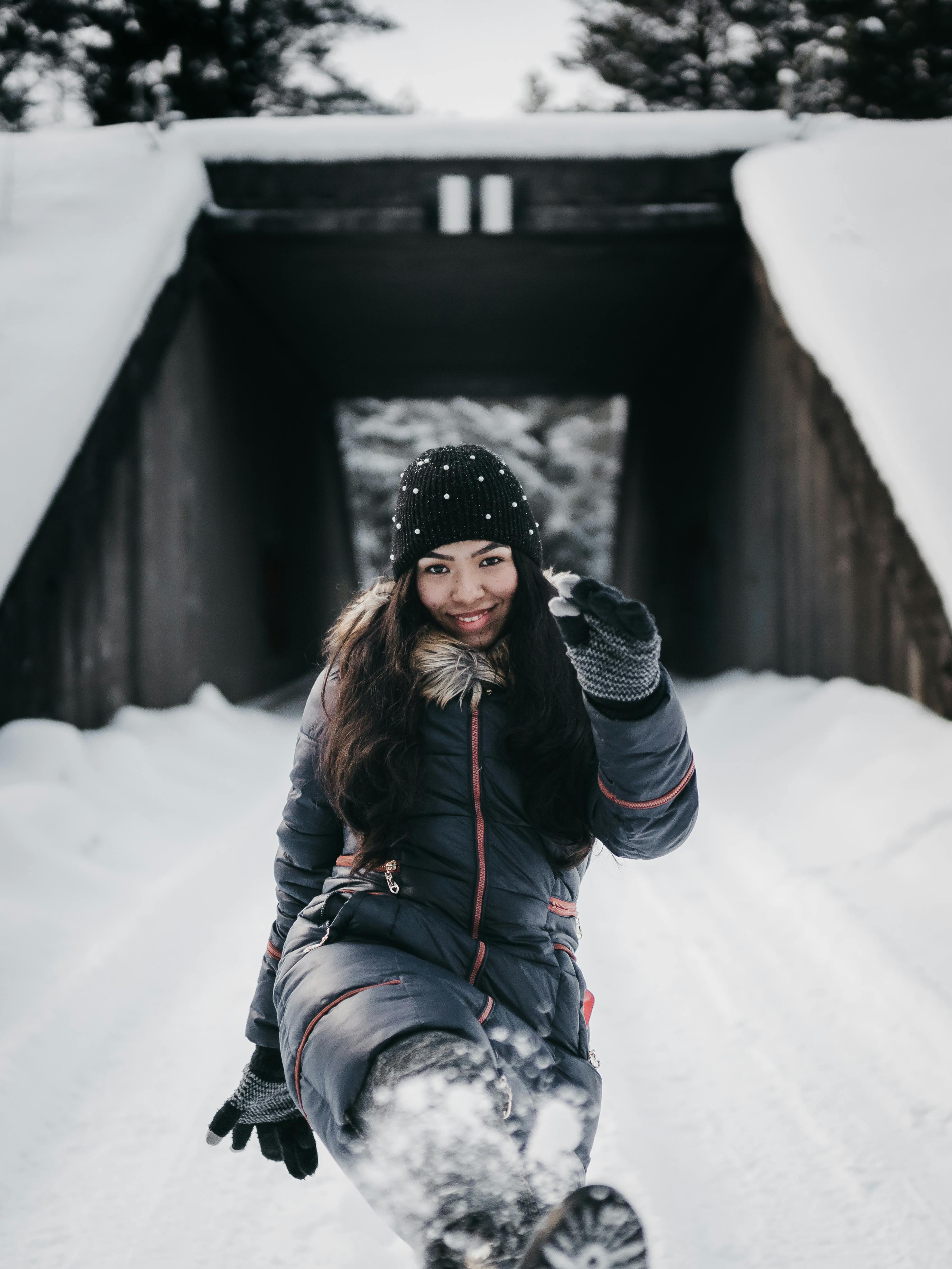 Cheerful ethnic woman kicking snow in winter park · Free Stock Photo