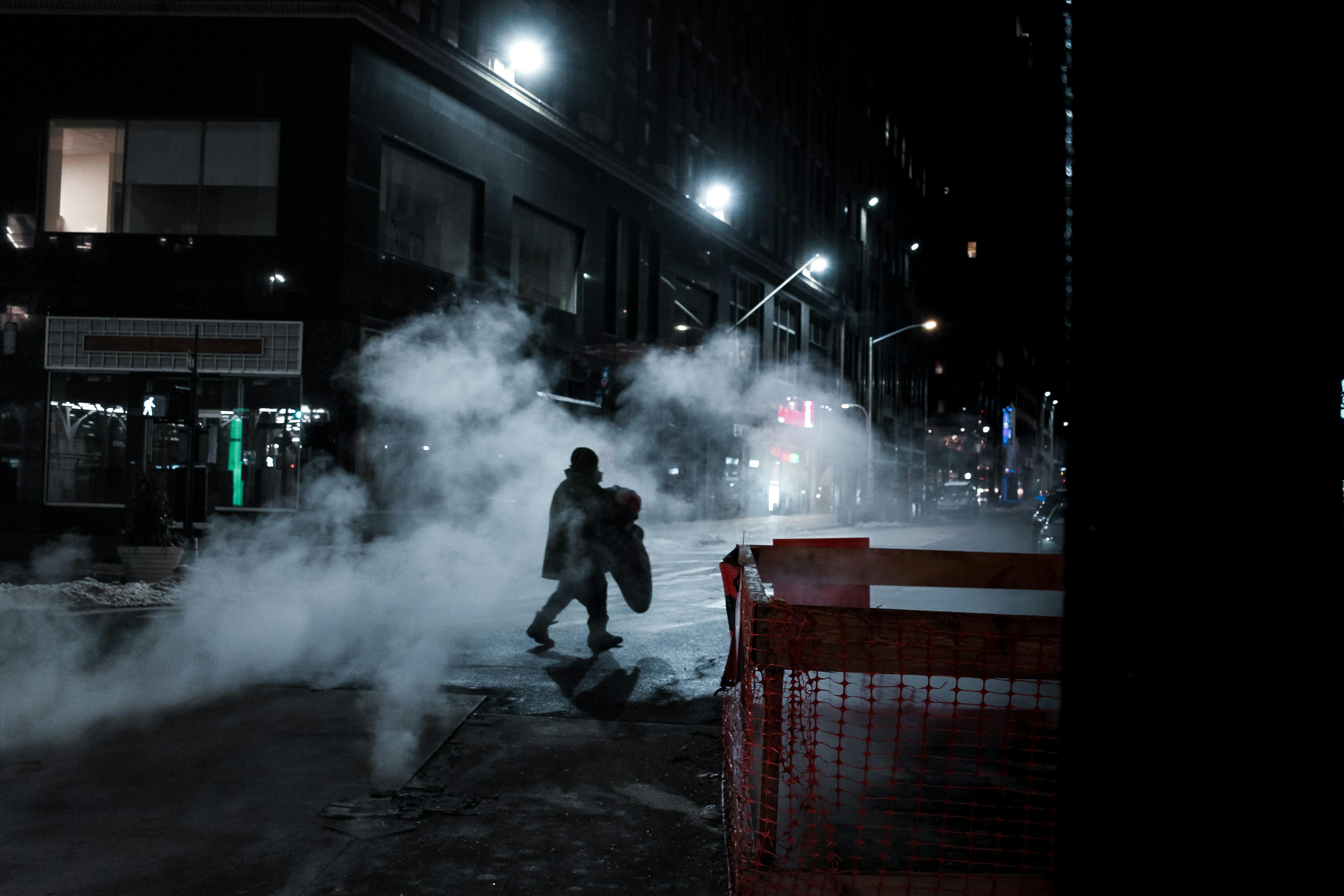 Unrecognizable person crossing road in dark street · Free Stock Photo