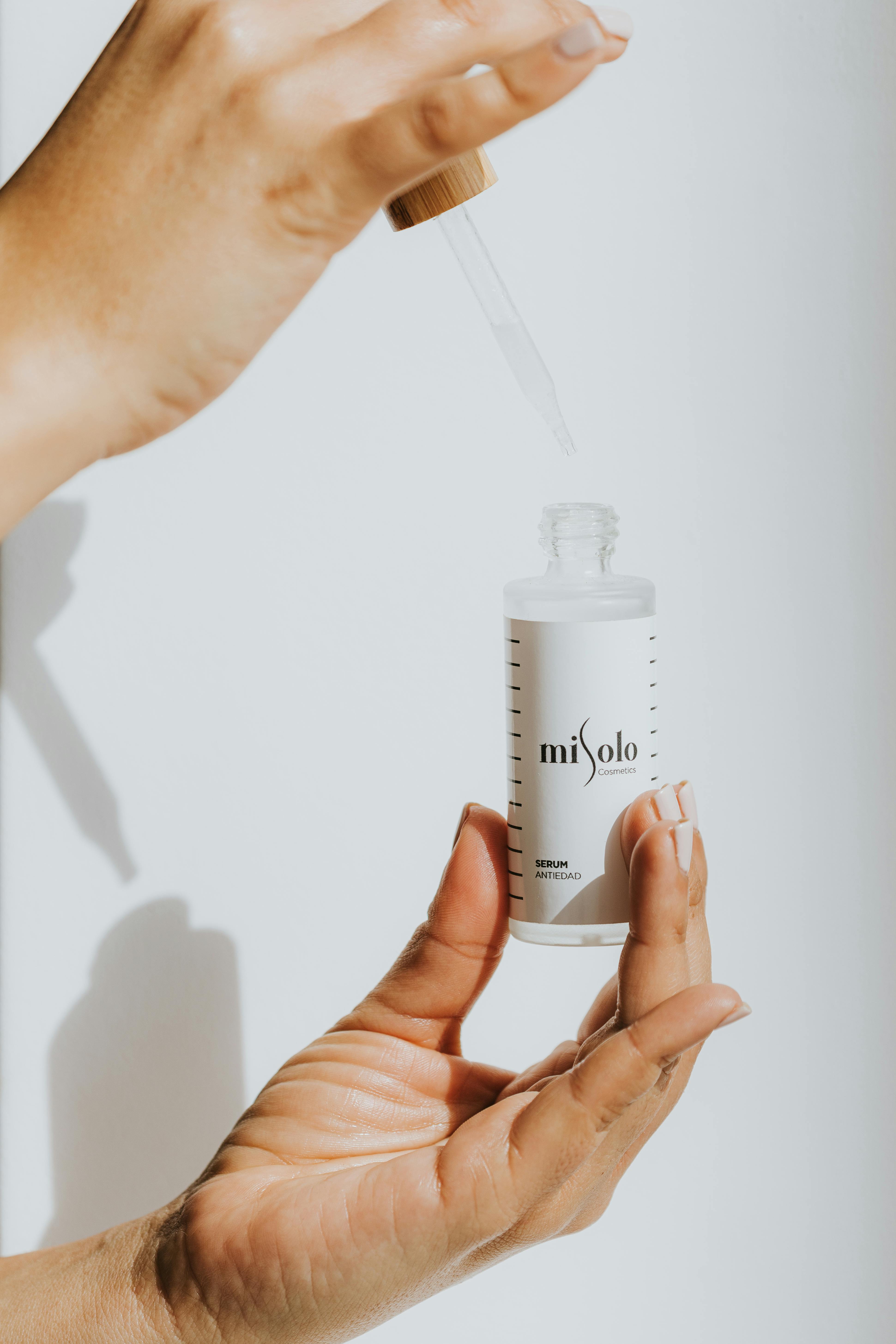 Person Holding a Dropper of Brown Bottle · Free Stock Photo