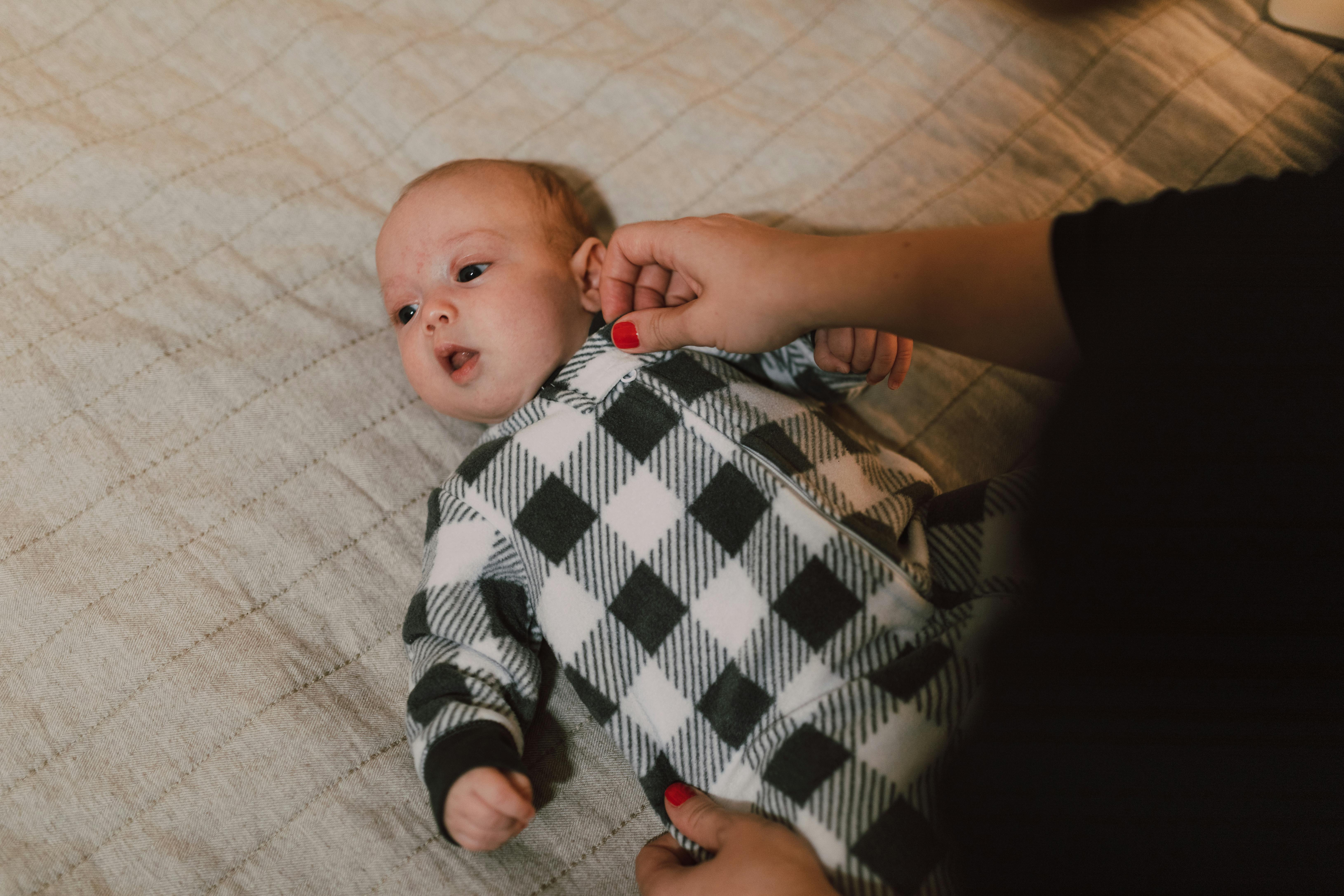 Baby in Gray and White Checkered Onesie Lying on Bed · Free Stock Photo