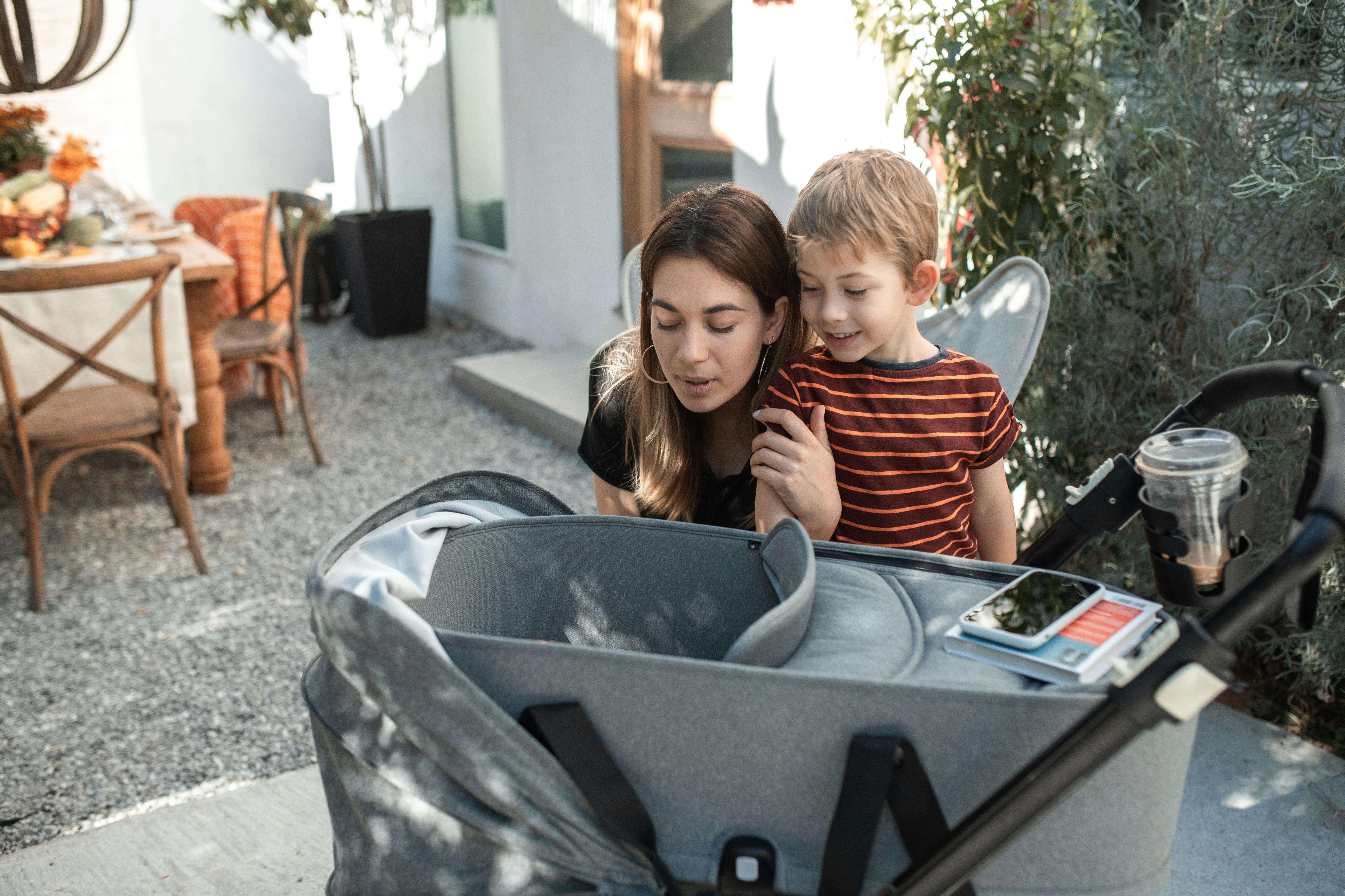 Mother and Kid Looking at the Baby Inside the Stroller · Free Stock Photo