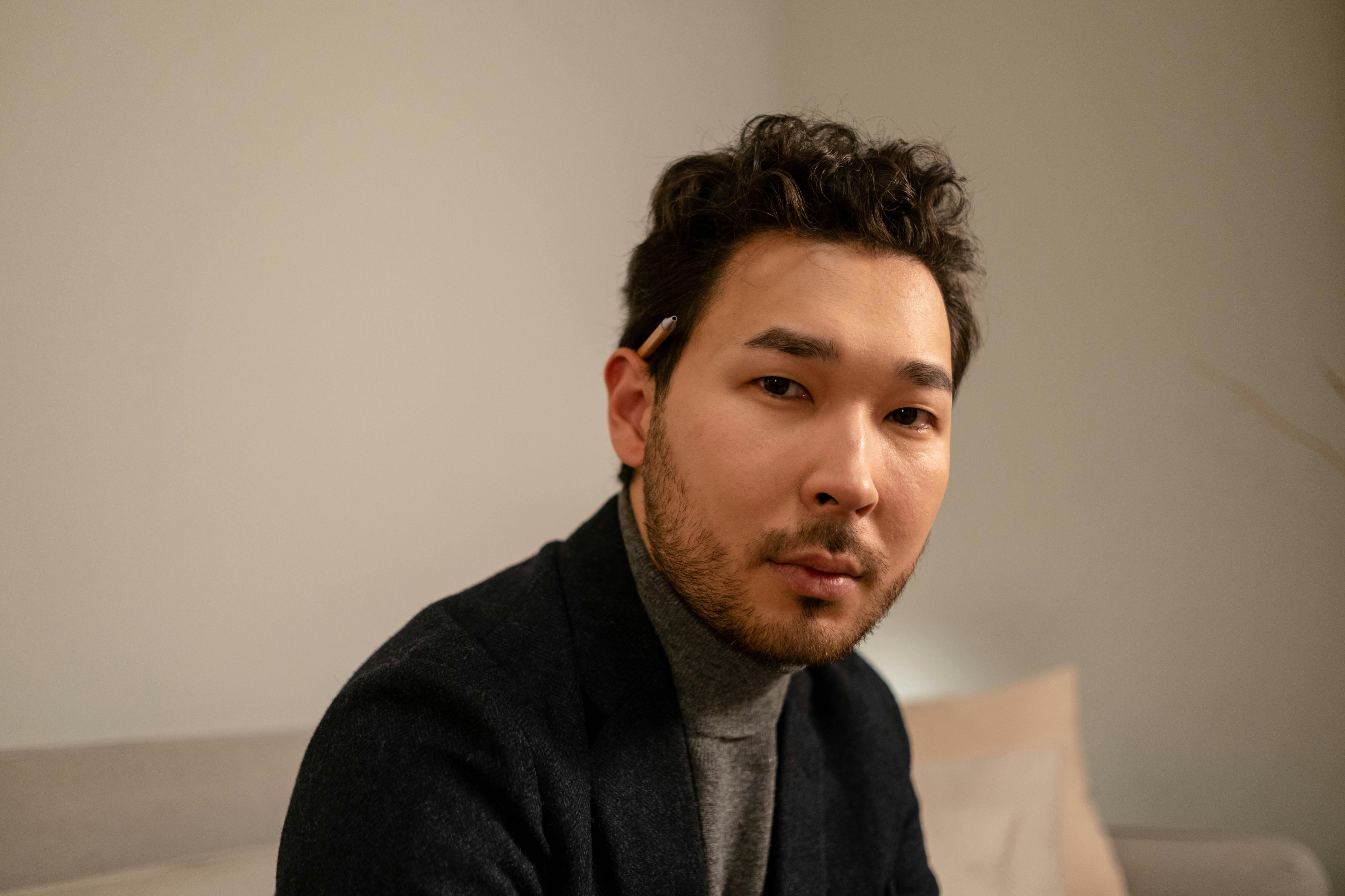 A Man in Black Jacket with a Pen Behind the Ear · Free Stock Photo