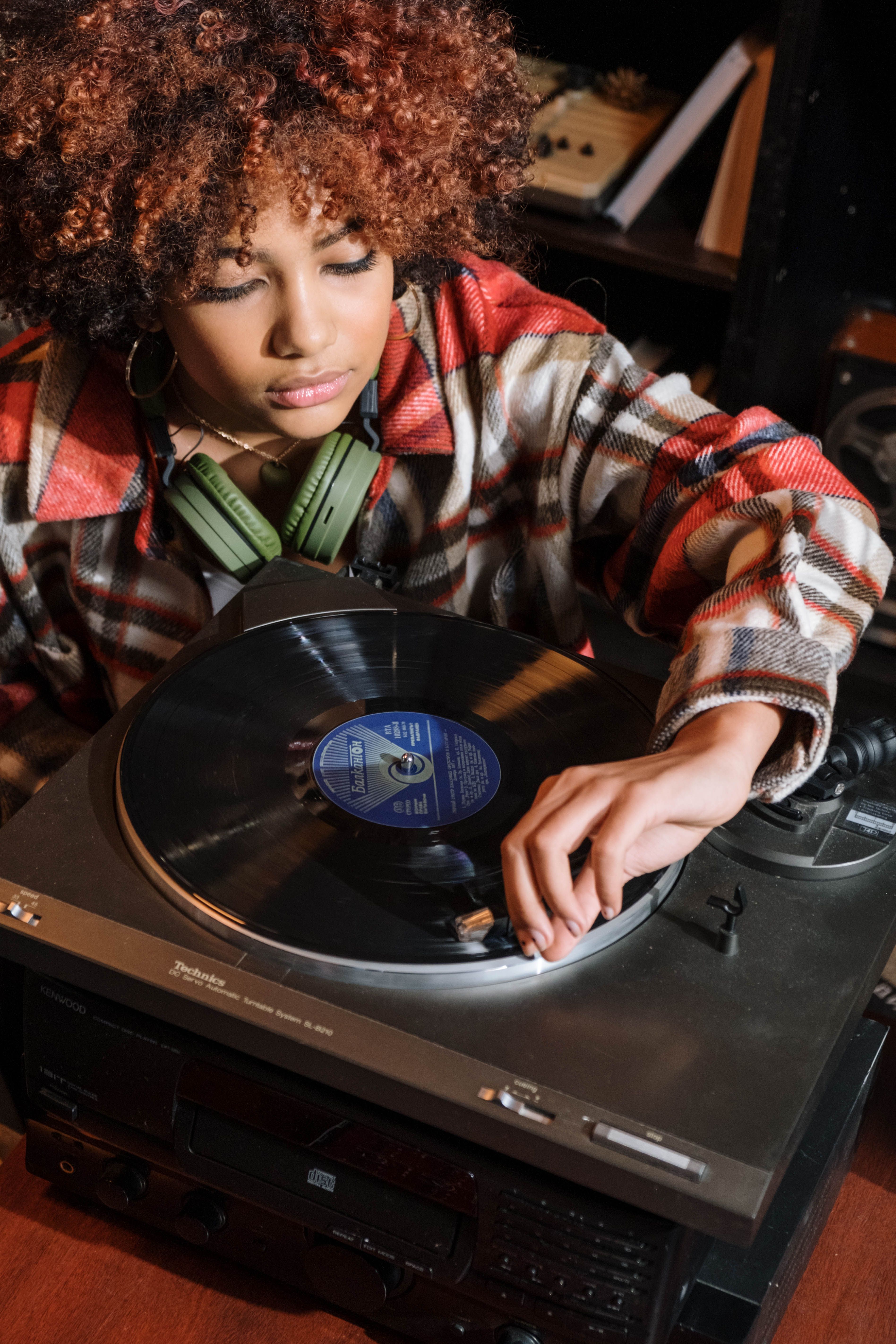 Woman in Plaid Shirt playing a Vinyl Record Player · Free Stock Photo