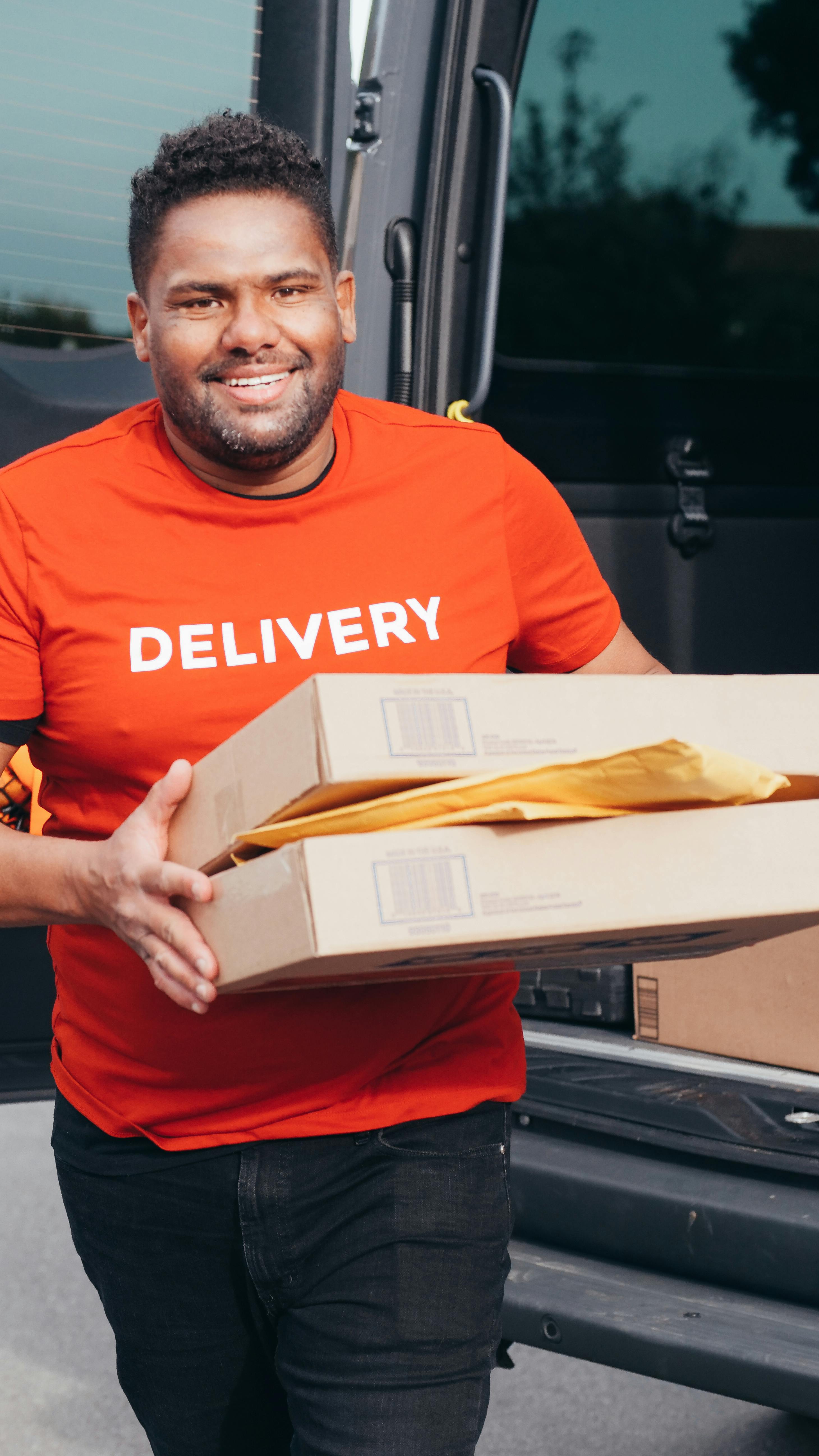 Man Carrying Boxes Beside a Van · Free Stock Photo