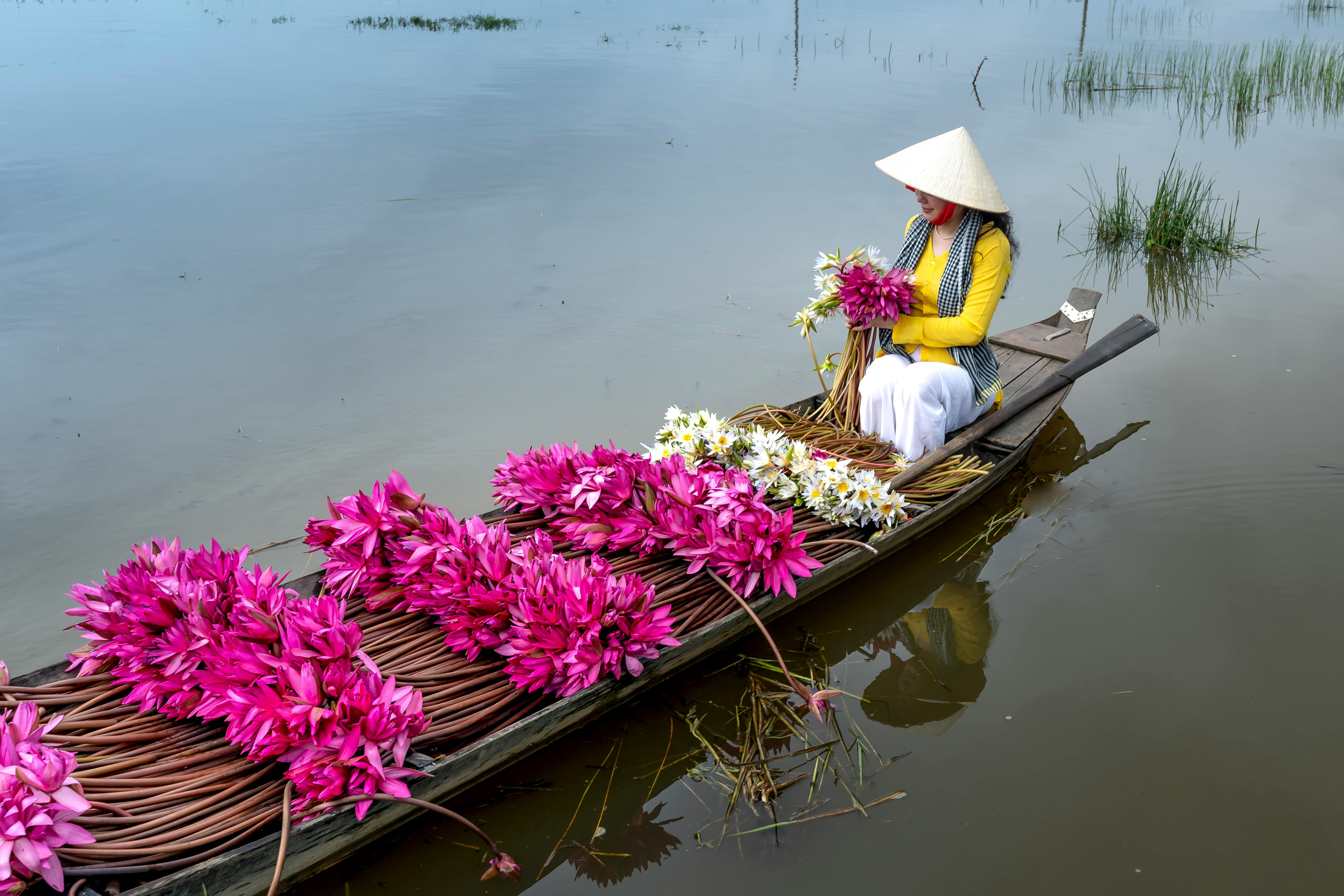 Woman Riding a Boat with Colorful Flowers · Free Stock Photo