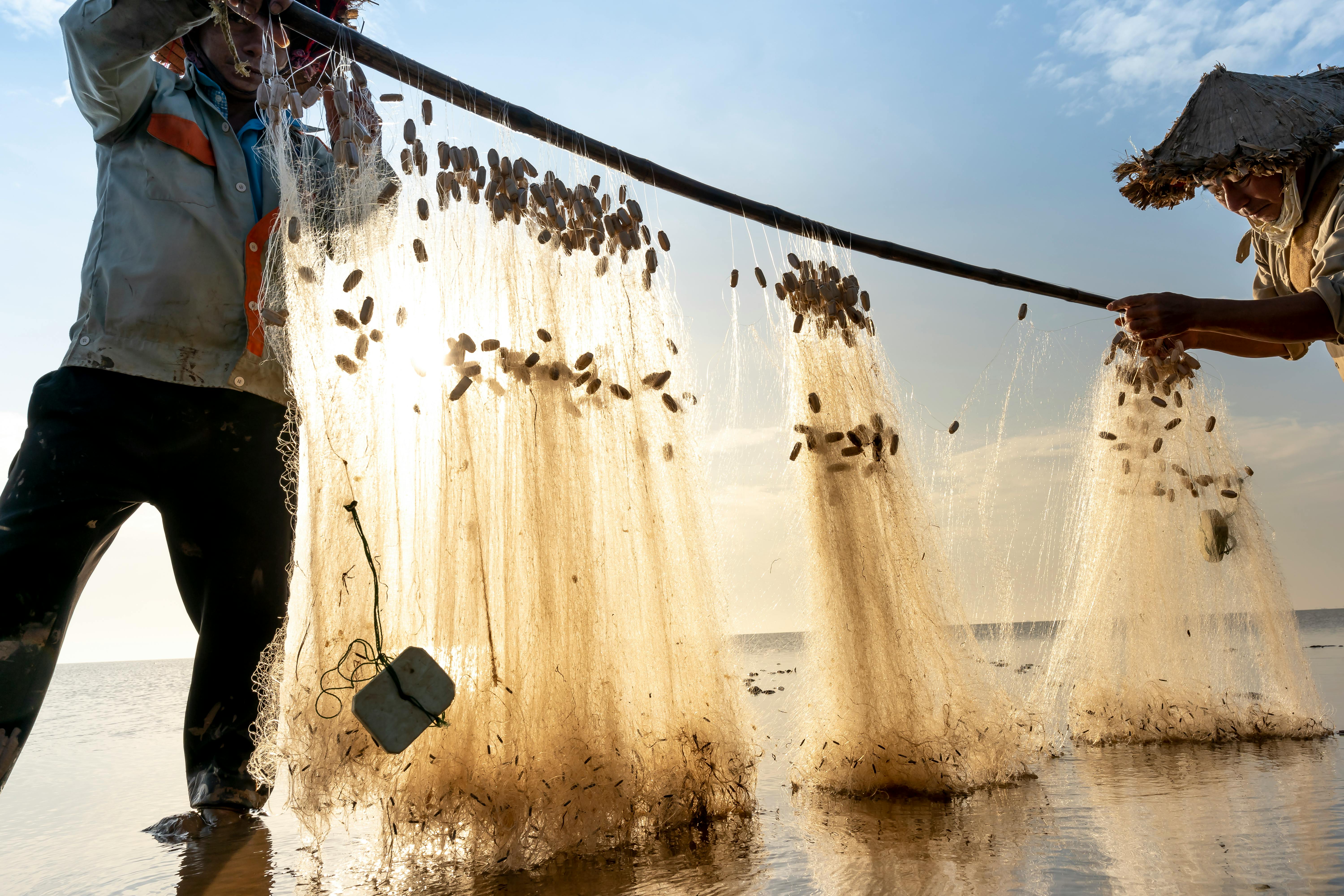 Men Throwing a Fishing Net in Sea at Dusk · Free Stock Photo