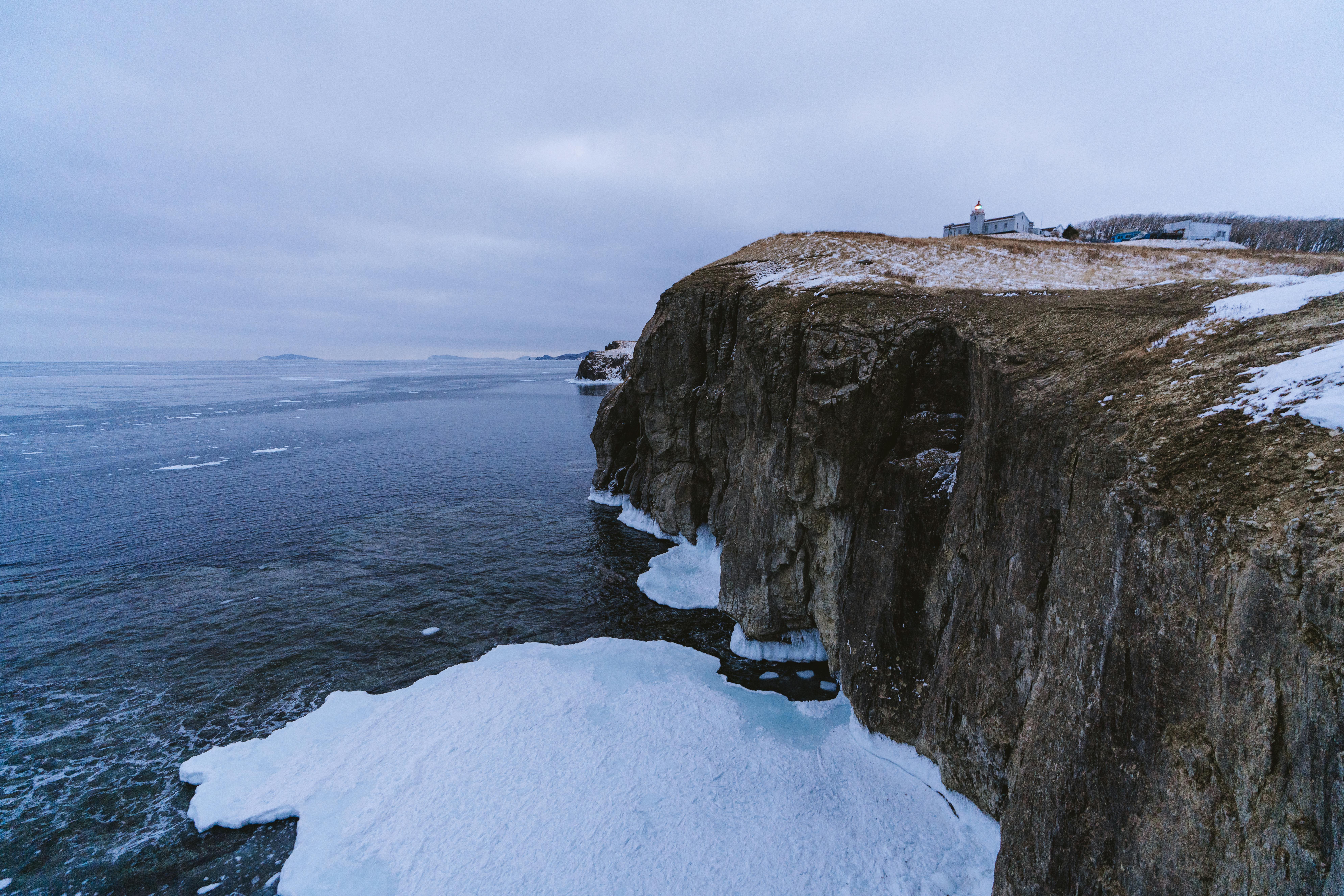 A Brown Cliff Mountain Along a Body of Water · Free Stock Photo