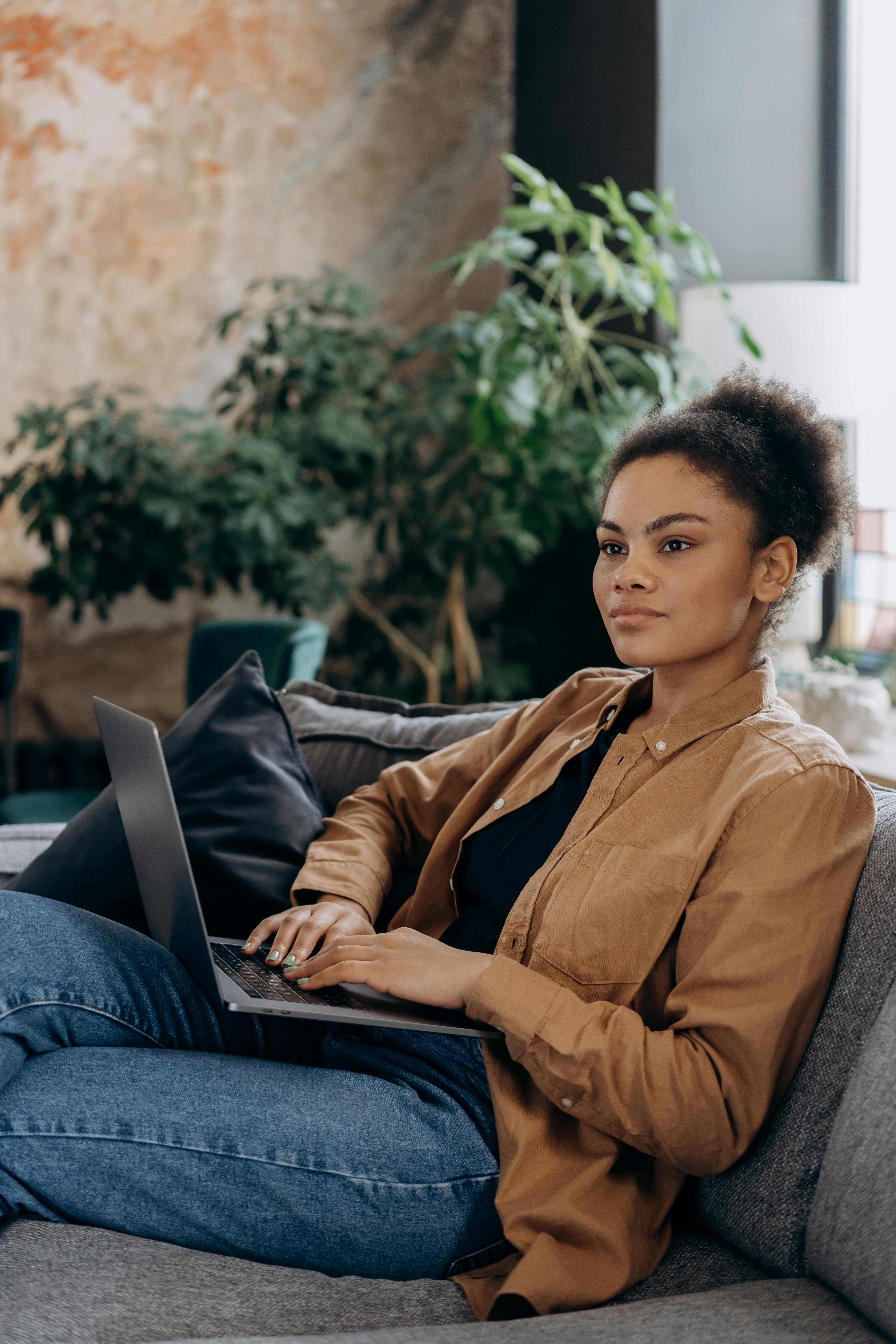 Woman Sitting on Sofa While Using a Laptop · Free Stock Photo