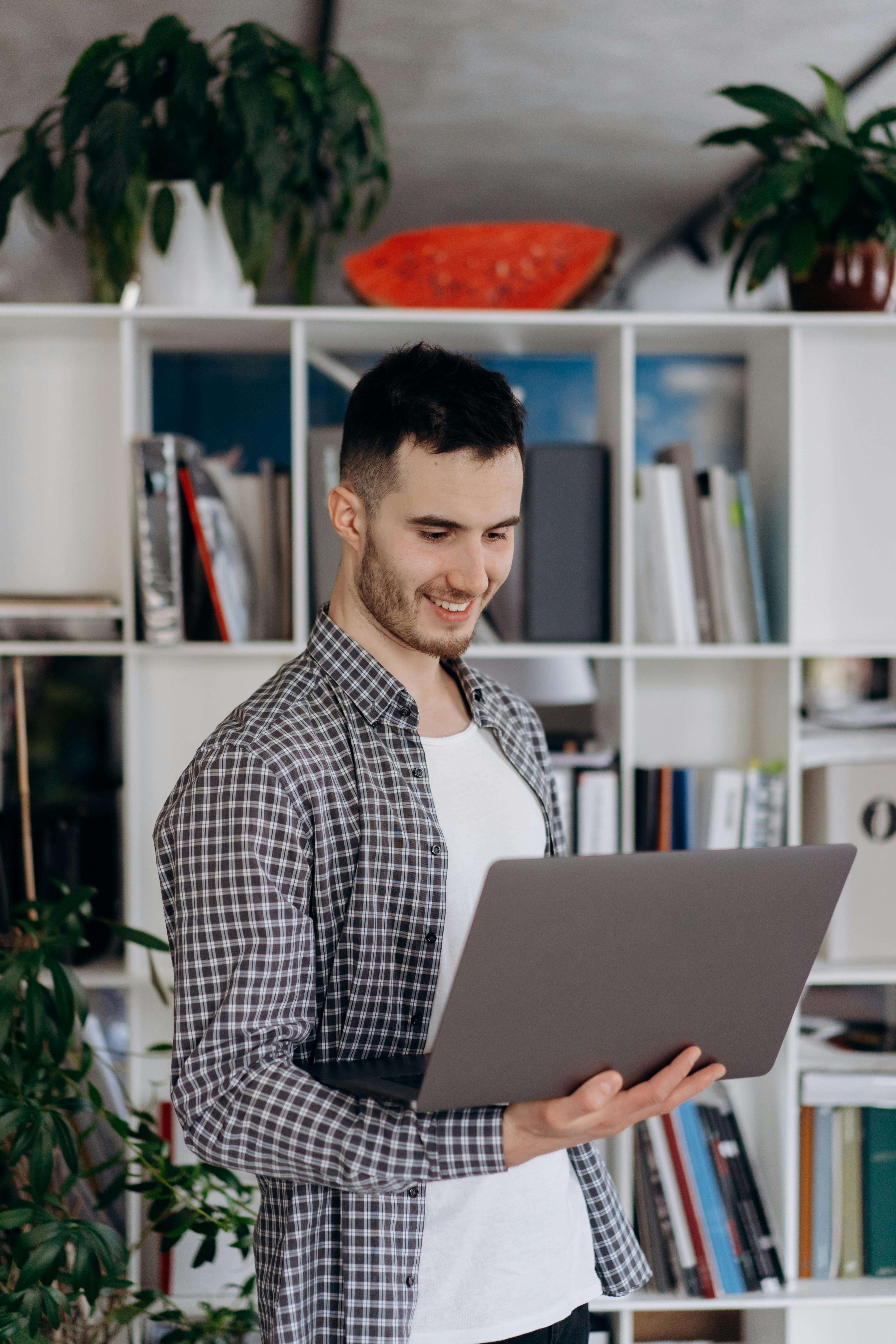 A Happy Man Looking at the Screen of a Laptop he is Holding · Free ...