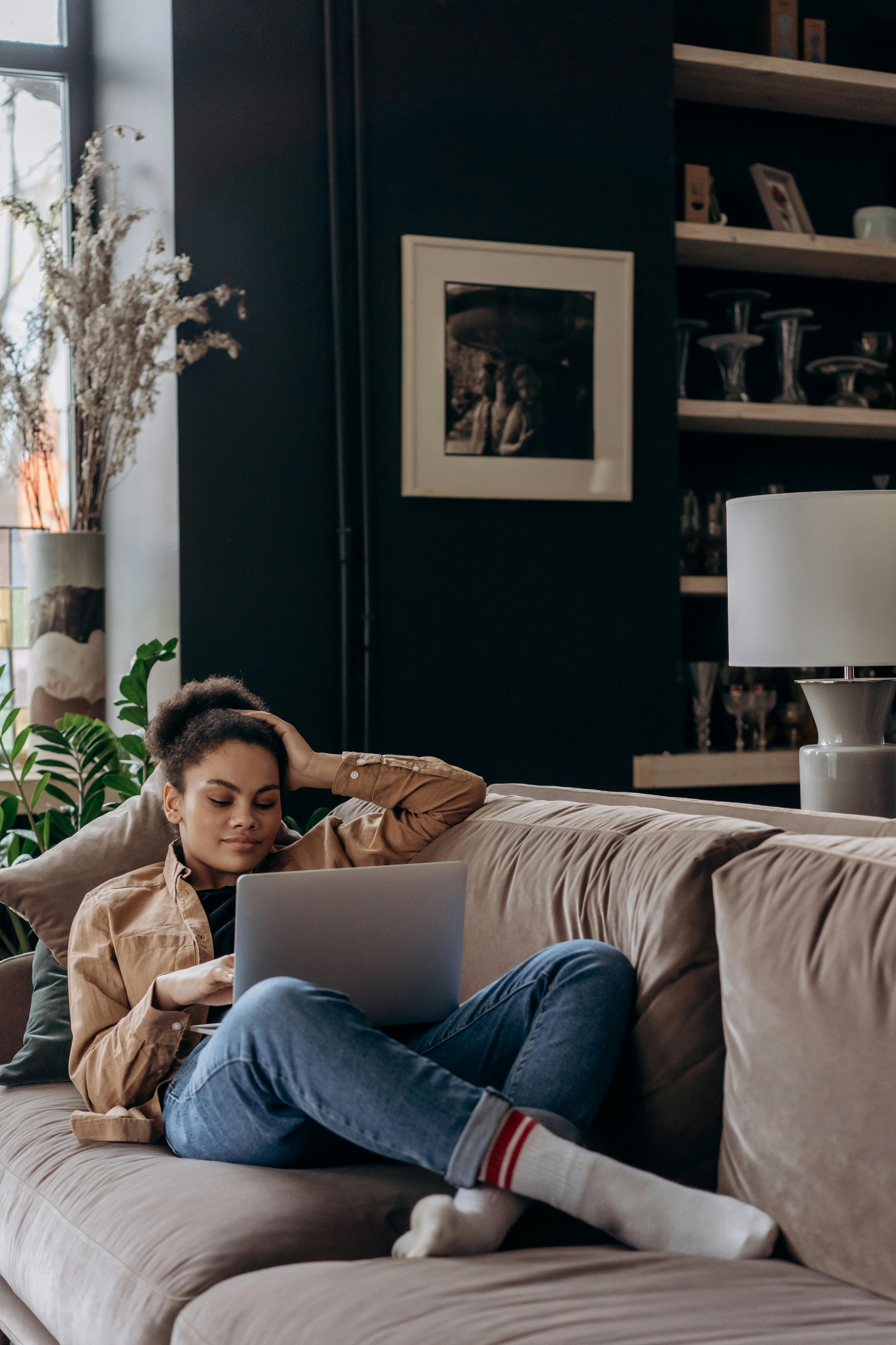 A Woman Lying on Sofa While using a Laptop · Free Stock Photo