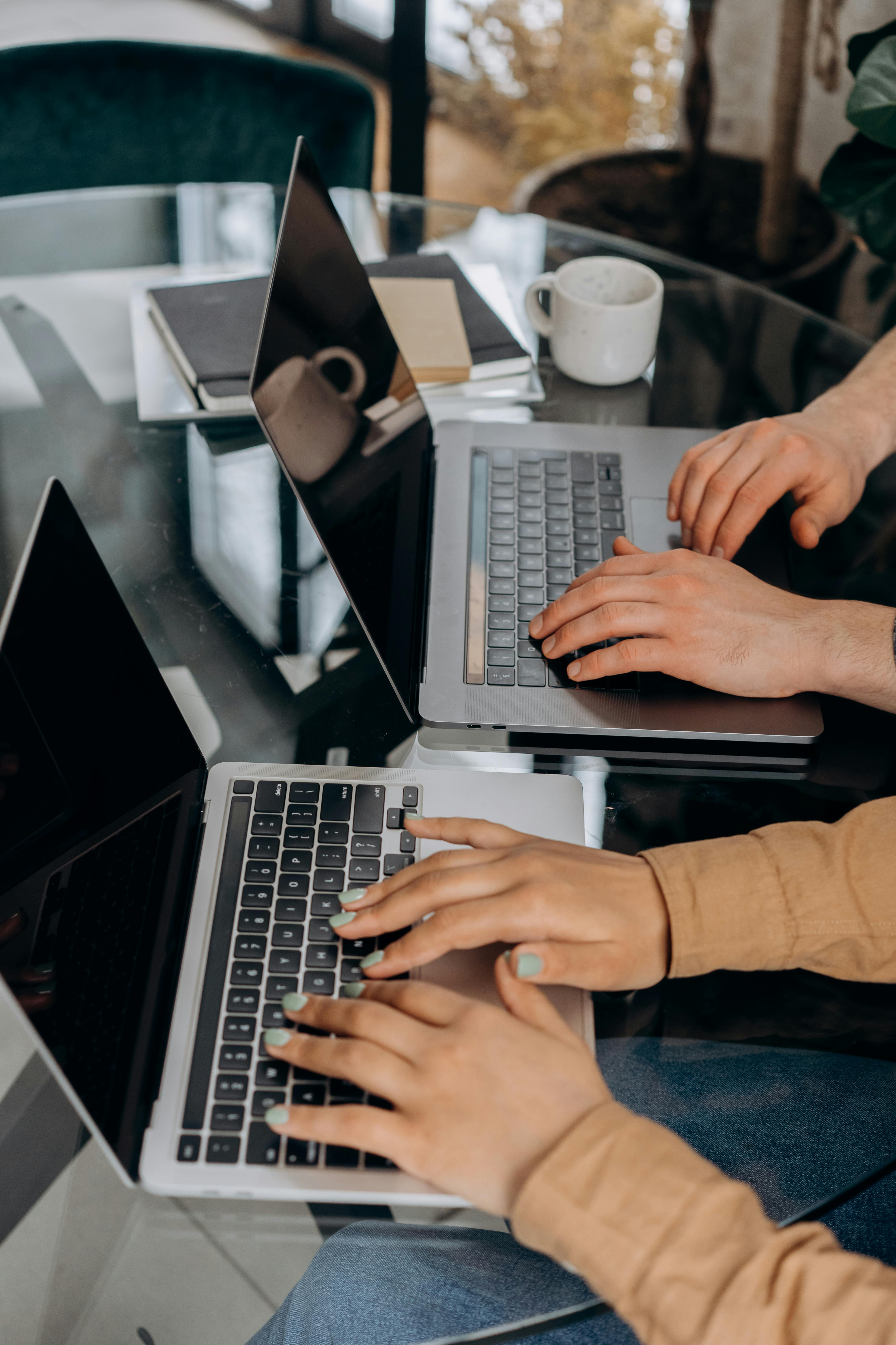 Two People Using Laptop On A Glass Table · Free Stock Photo
