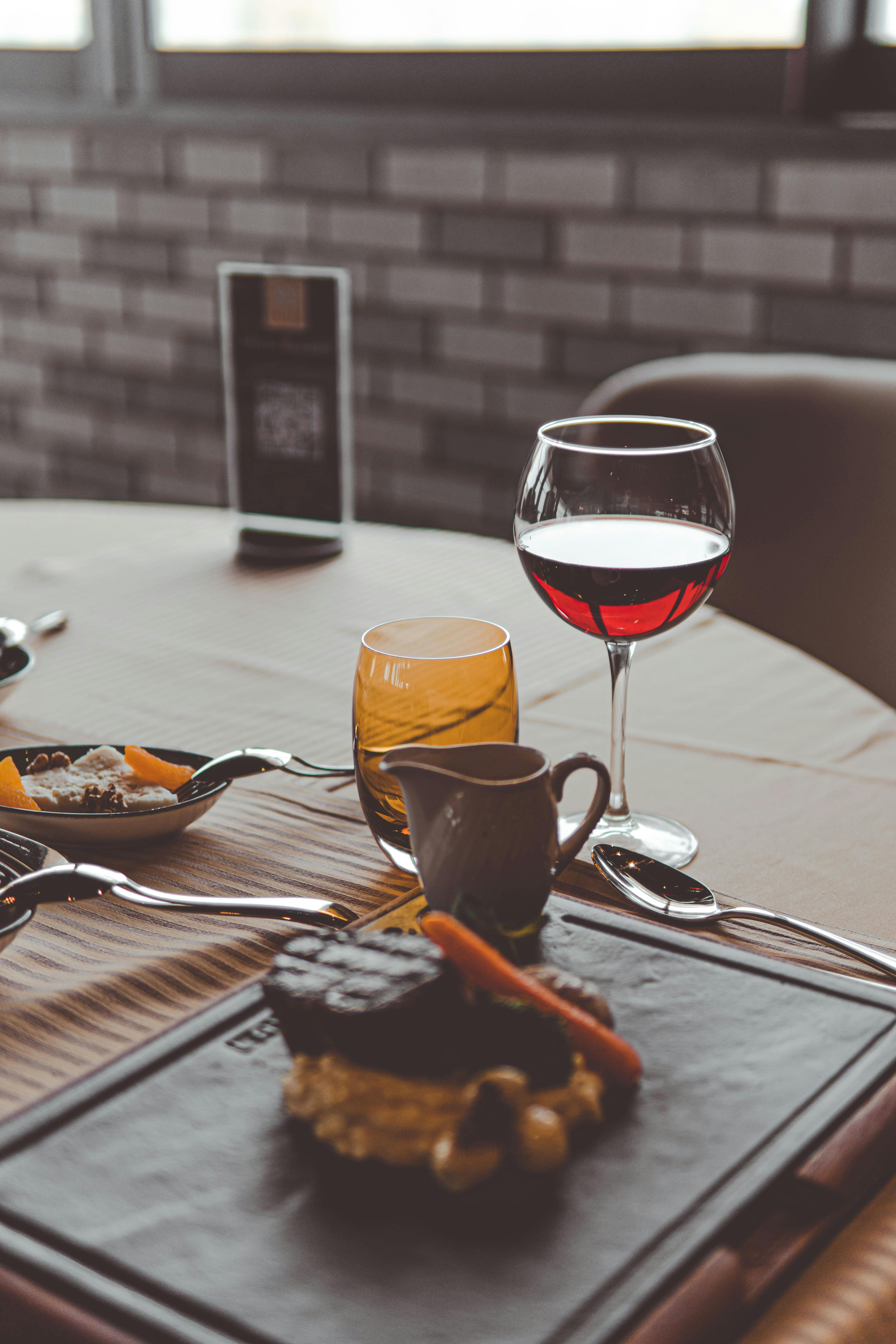 A Wine Glass with Wine on a Table with Flatwares · Free Stock Photo