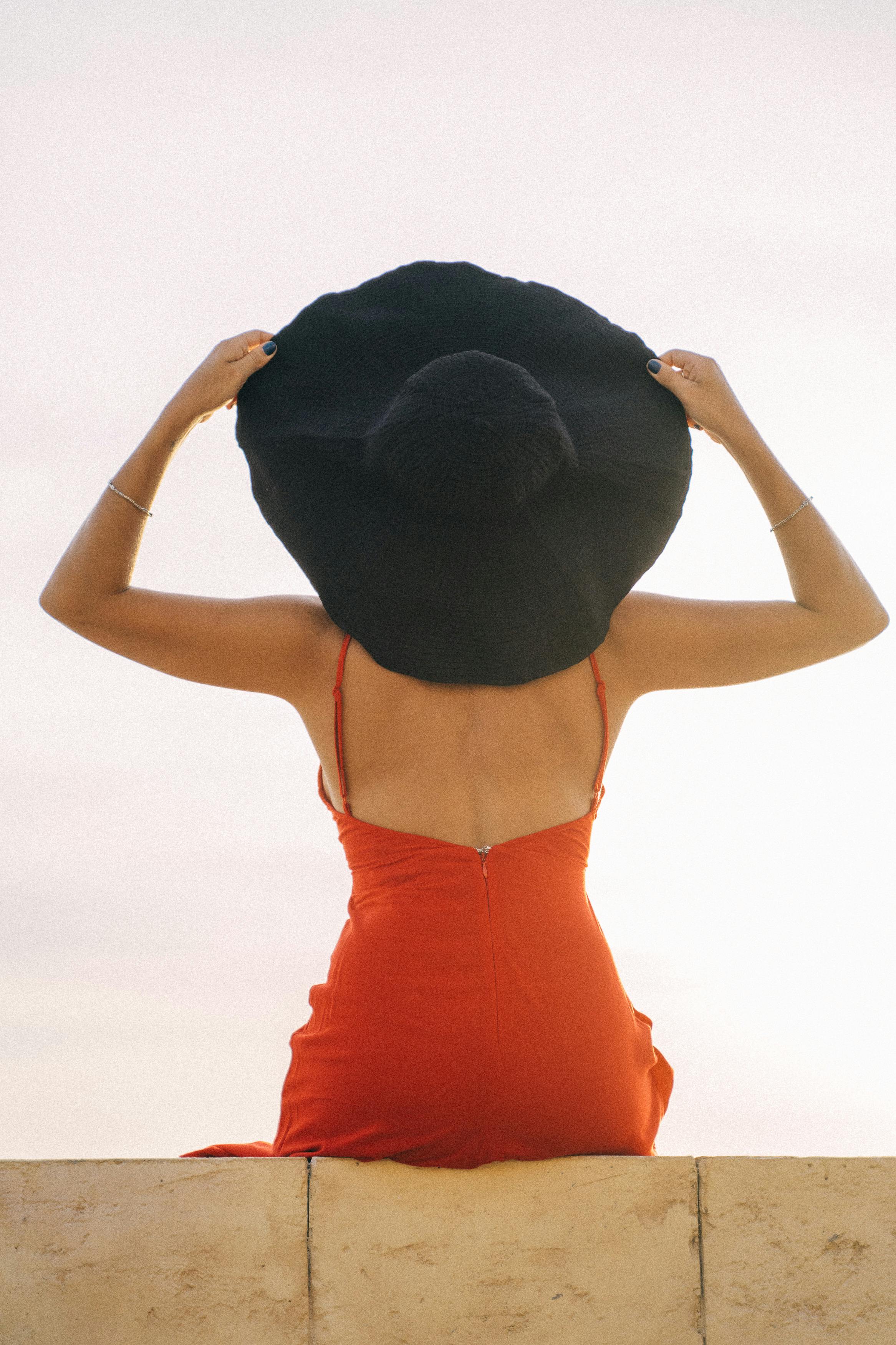 Back View of Woman Sitting Wearing Black Sun Hat · Free Stock Photo