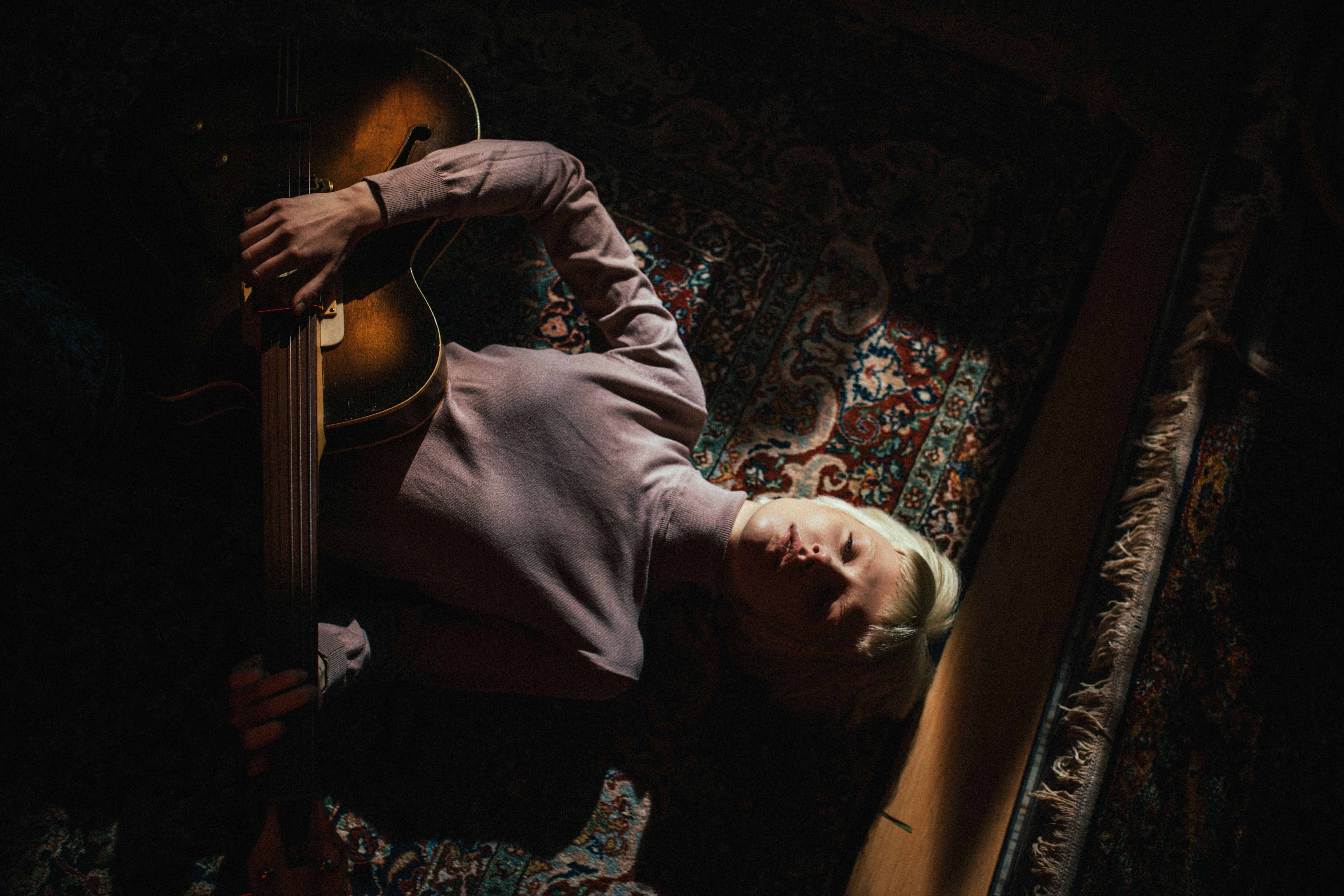 A Woman Lying Down While Playing the Guitar · Free Stock Photo