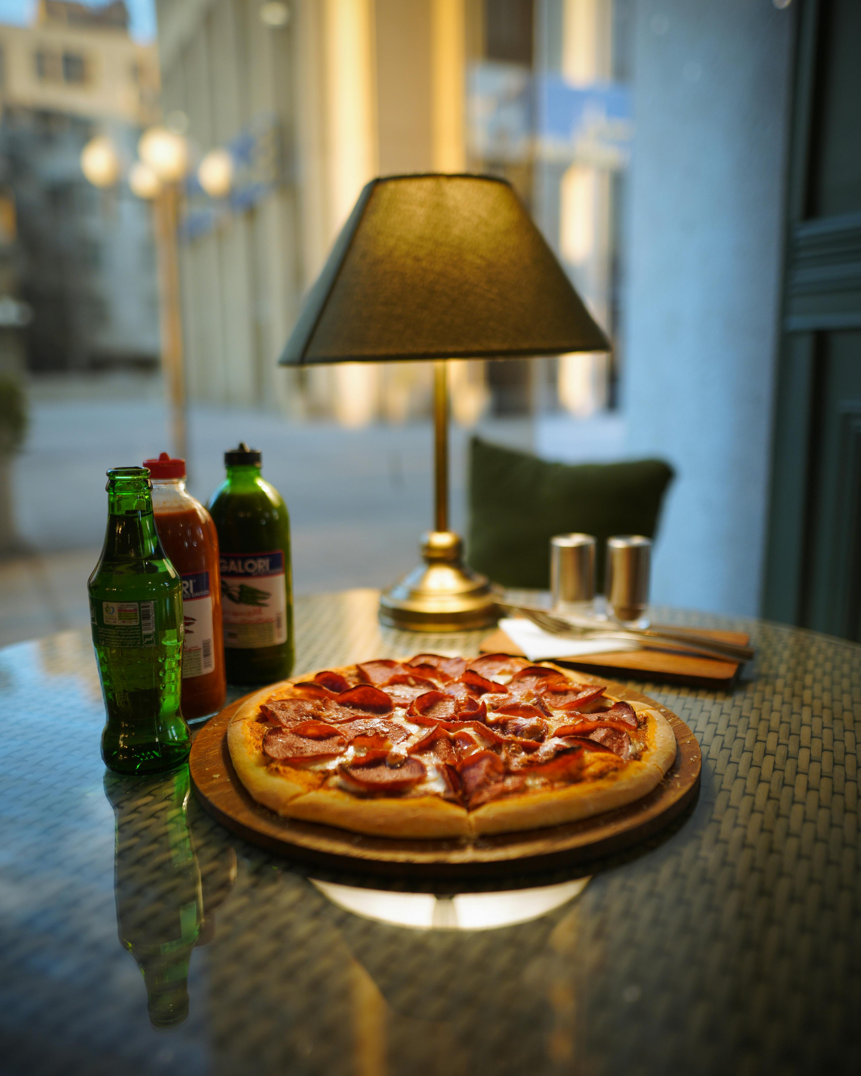 Close-Up Shot of a Pizza beside Condiments on a Table · Free Stock Photo