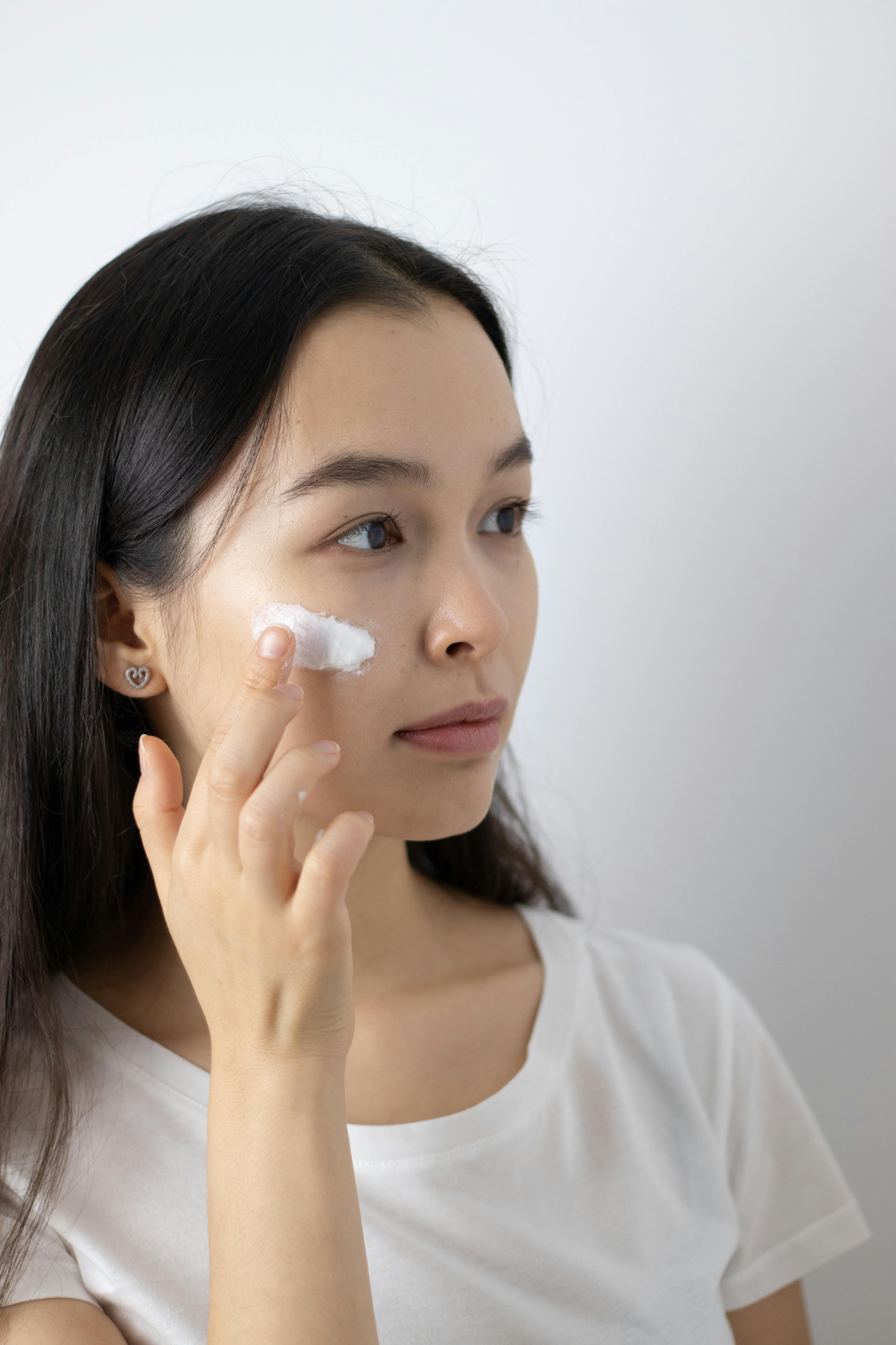 A Woman Applying a Skin Care Product on Her Face · Free Stock Photo