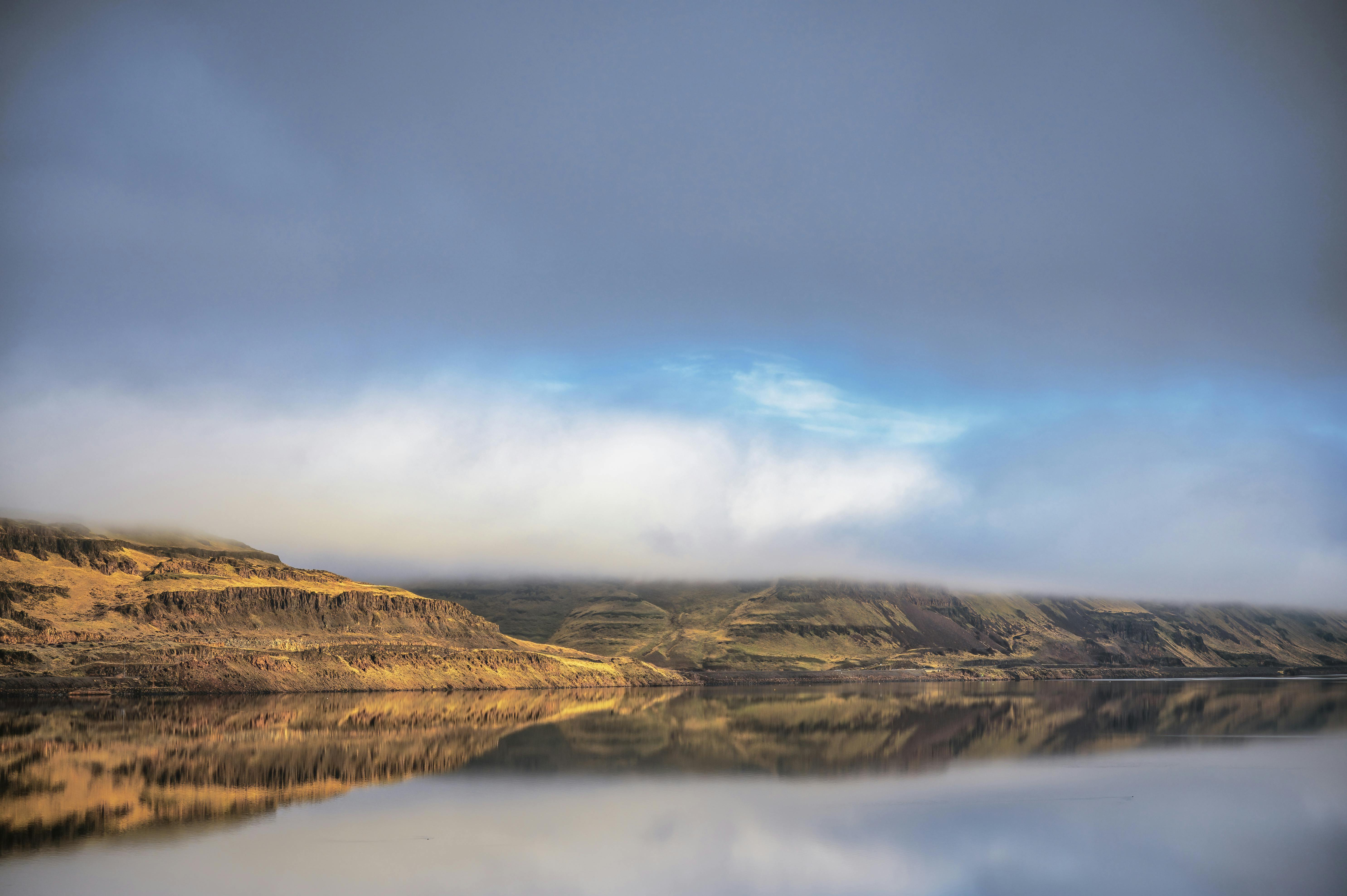 Scenic view of calm lake near hills · Free Stock Photo