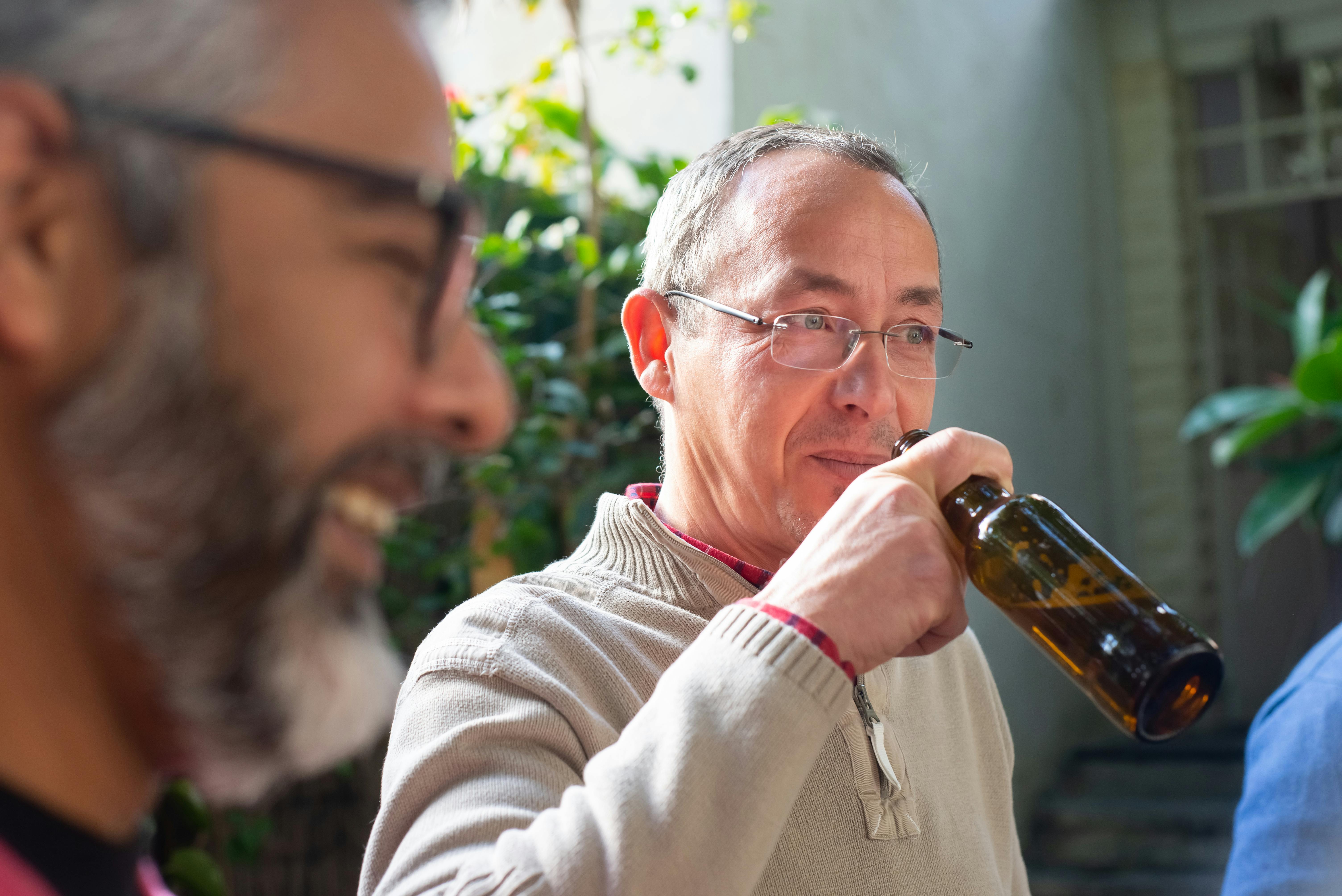 Photo of an Adult with Eyeglasses Drinking From a Brown Beer Bottle ...
