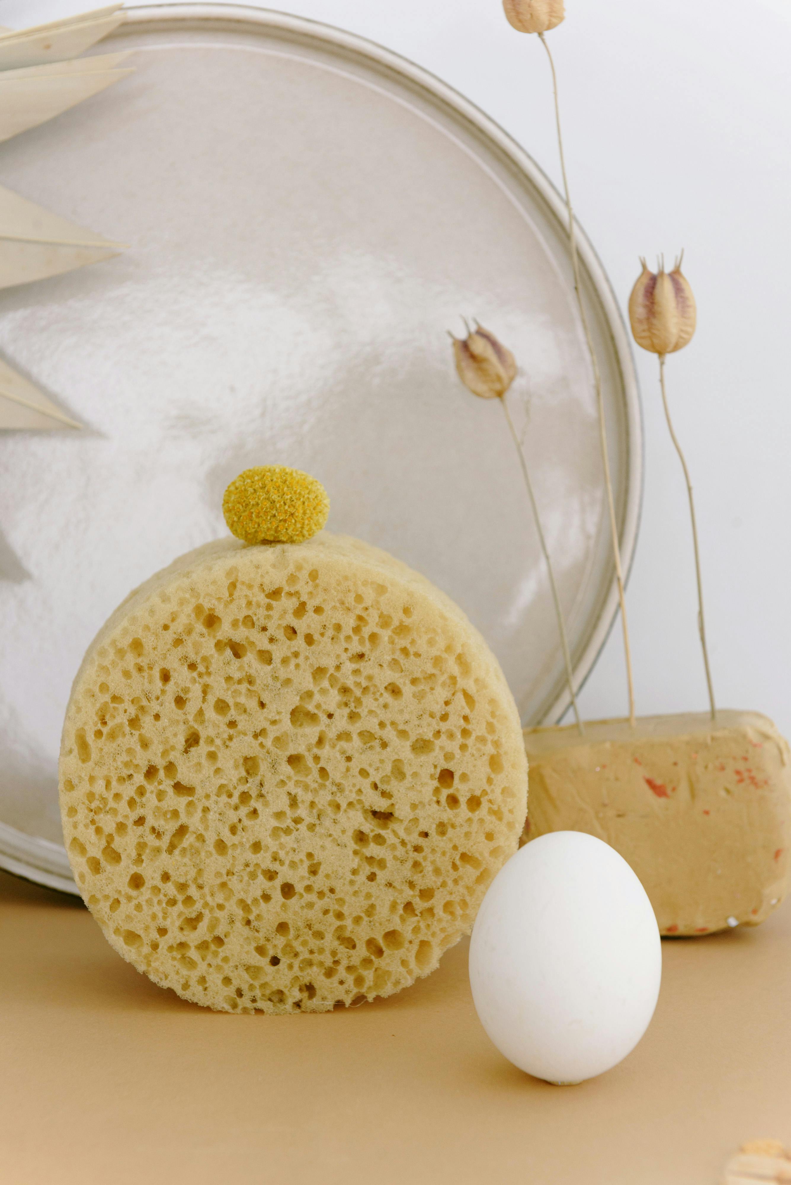 White Egg, Yellow Sponge, Dried Flowers and Round Glass on a Flat ...