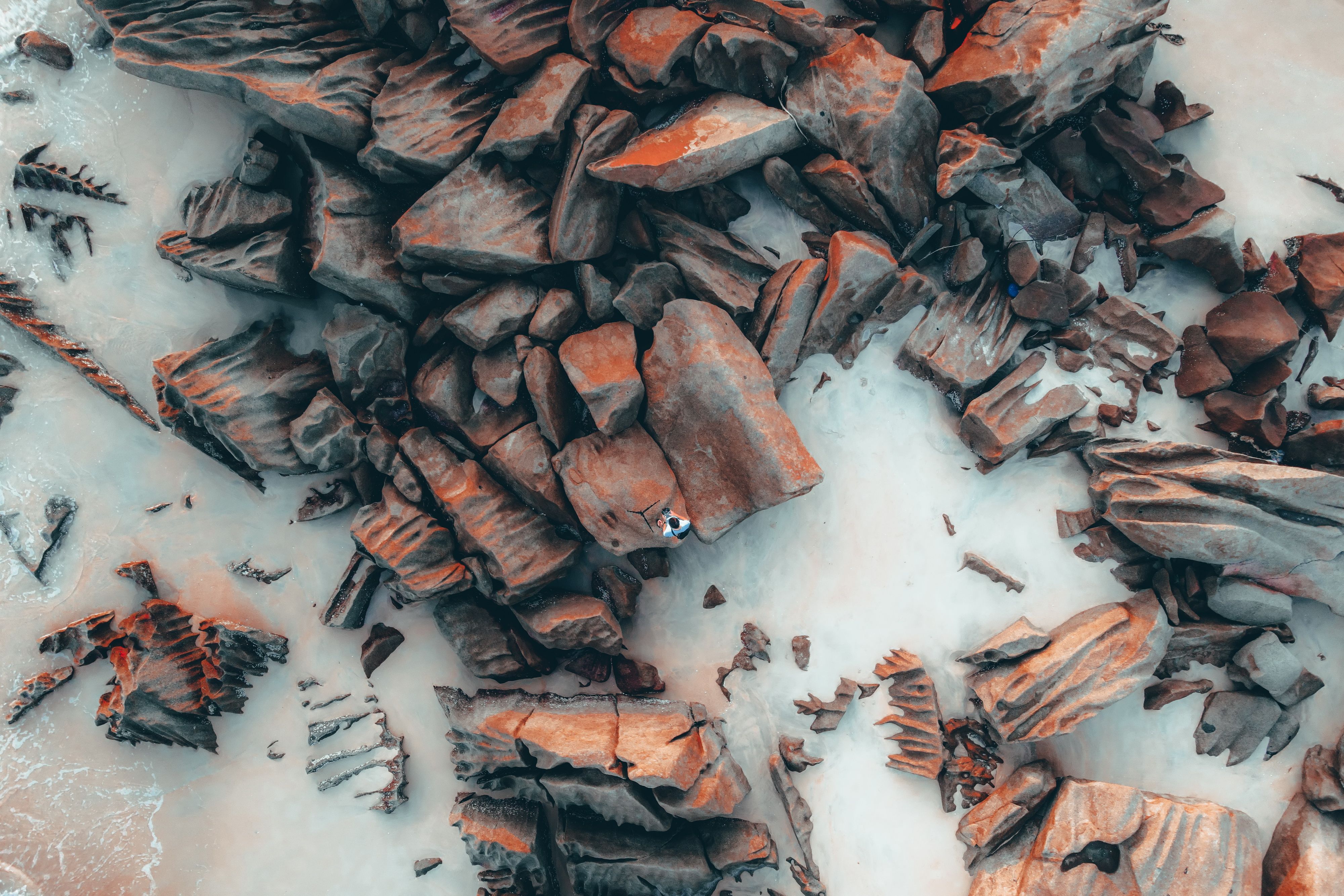 Rocky cliff on sandy seacoast under sundown sky · Free Stock Photo