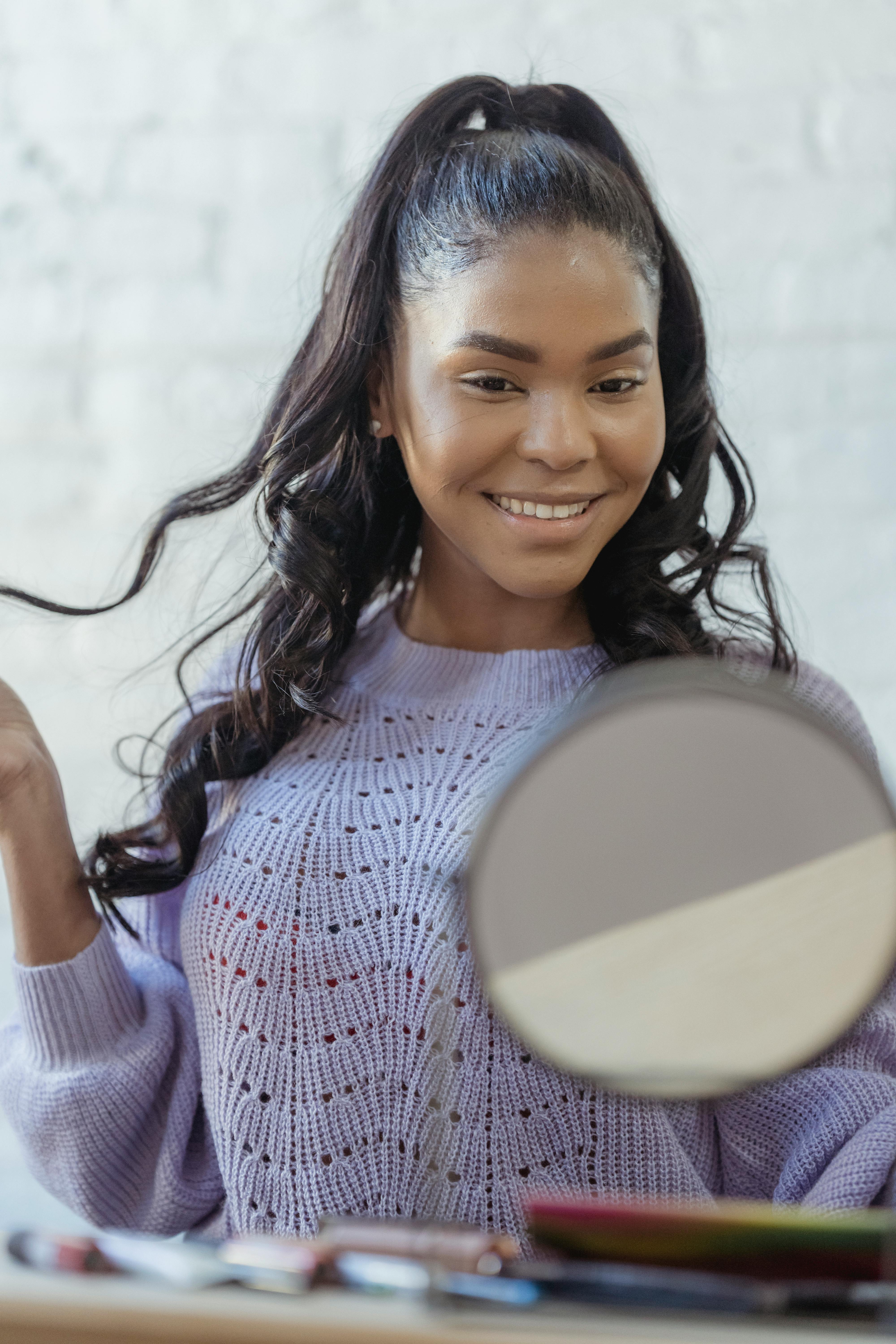 Cheerful confident black woman admiring reflection in mirror · Free ...