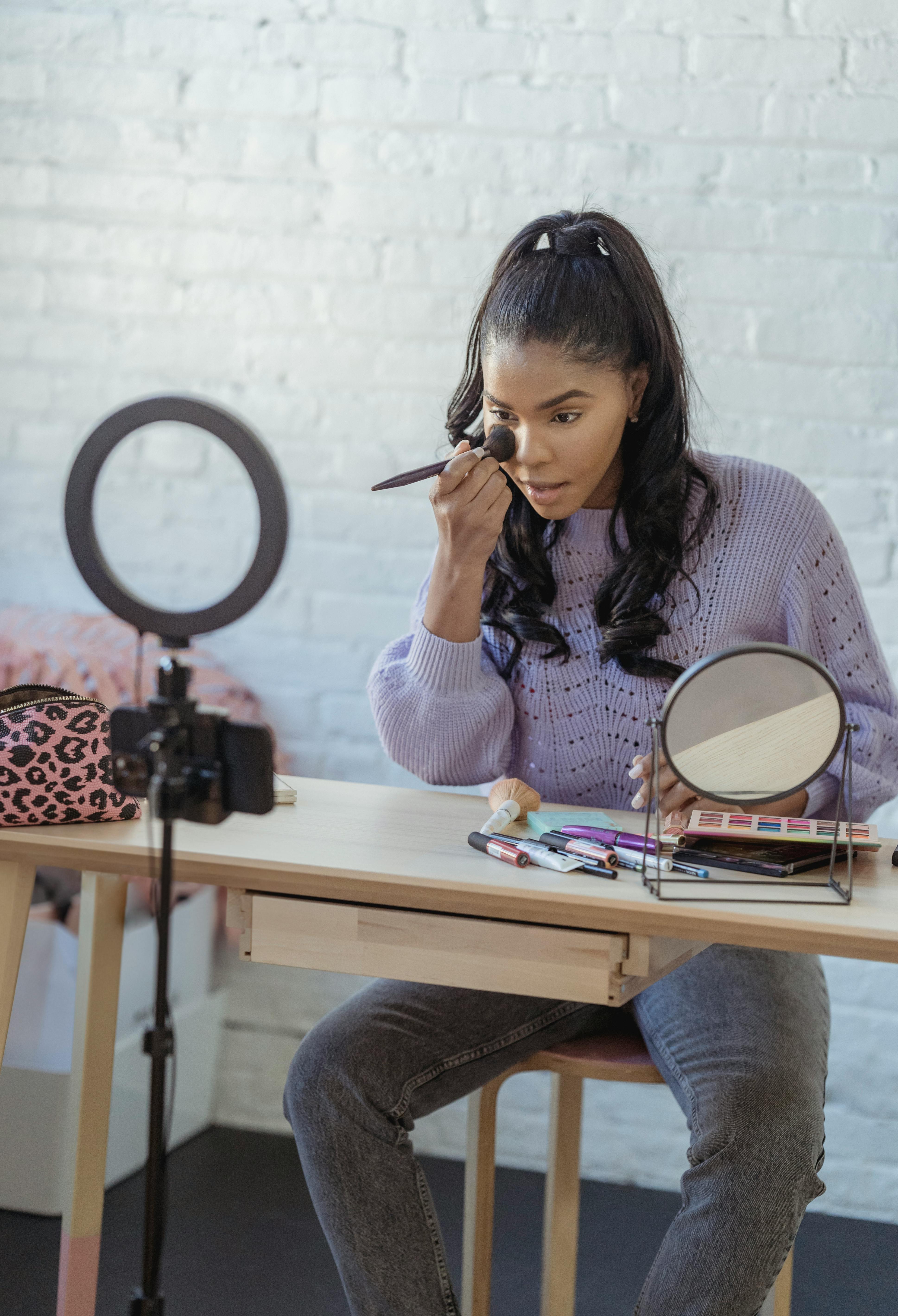 Black woman applying makeup with brush during video tutorial · Free ...