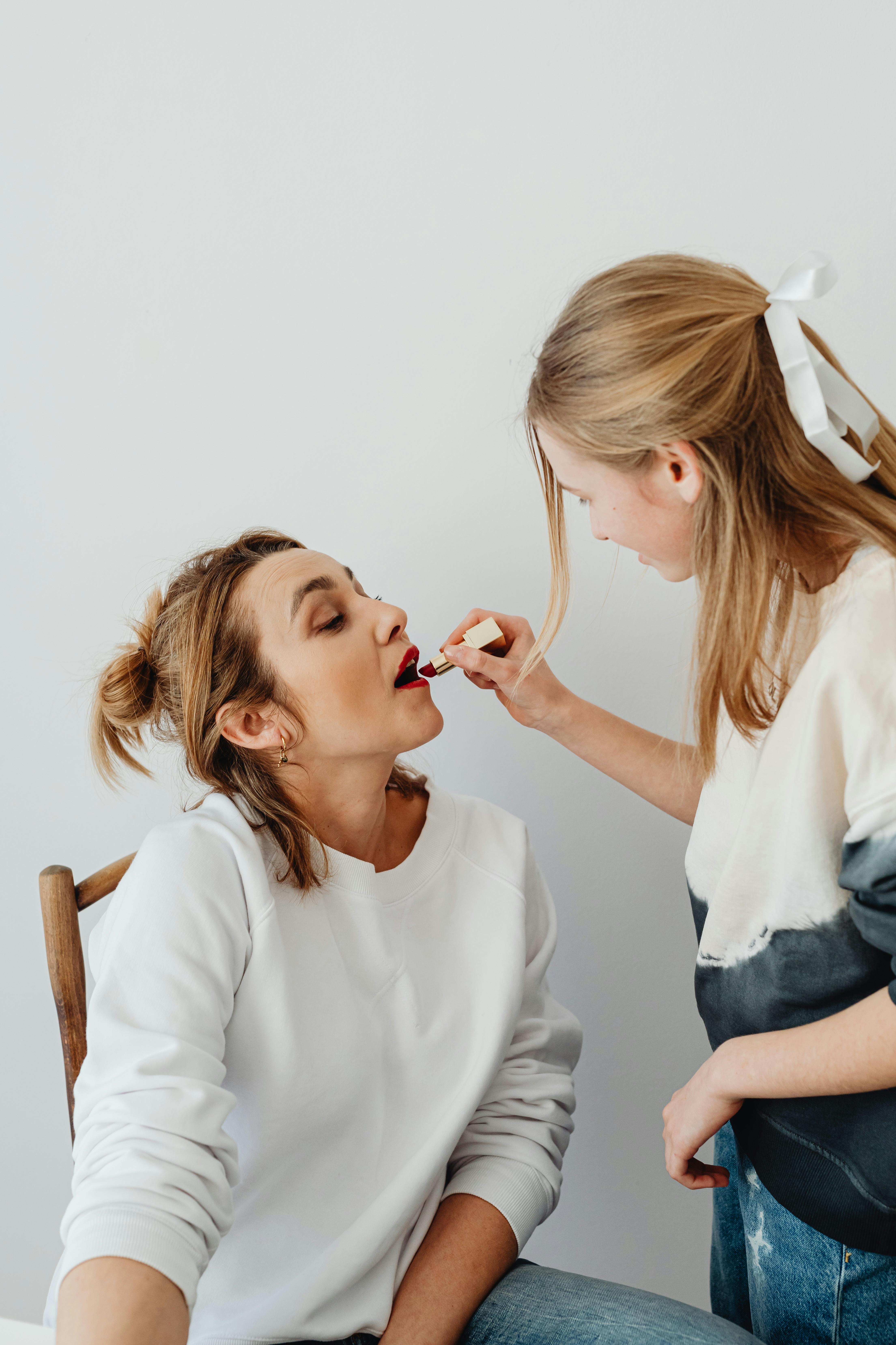 Daughter Applying Red Lipstick on Her Mother's Lips · Free Stock Photo