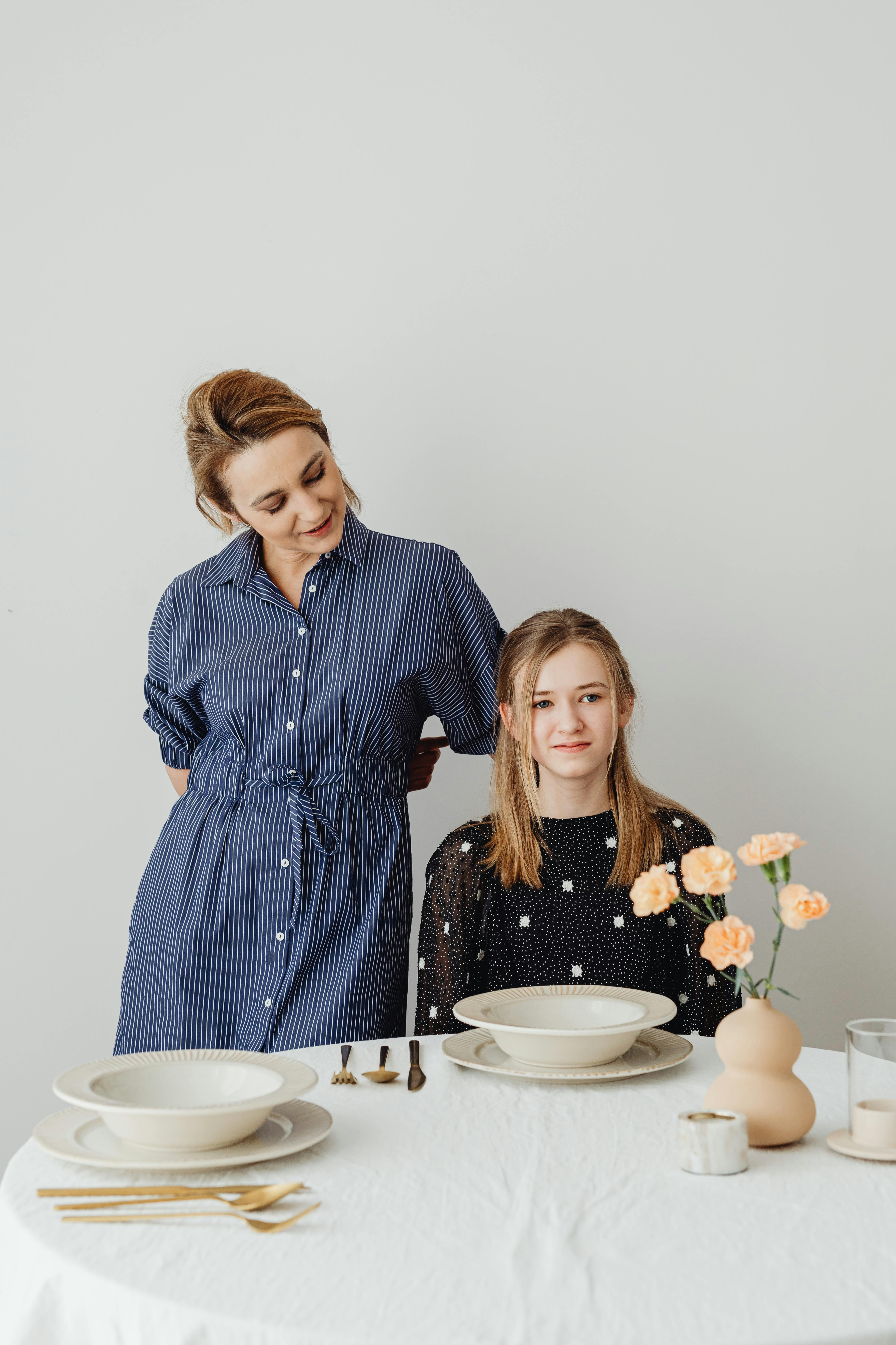 A Mother Standing Beside Her Sitting Daughter · Free Stock Photo
