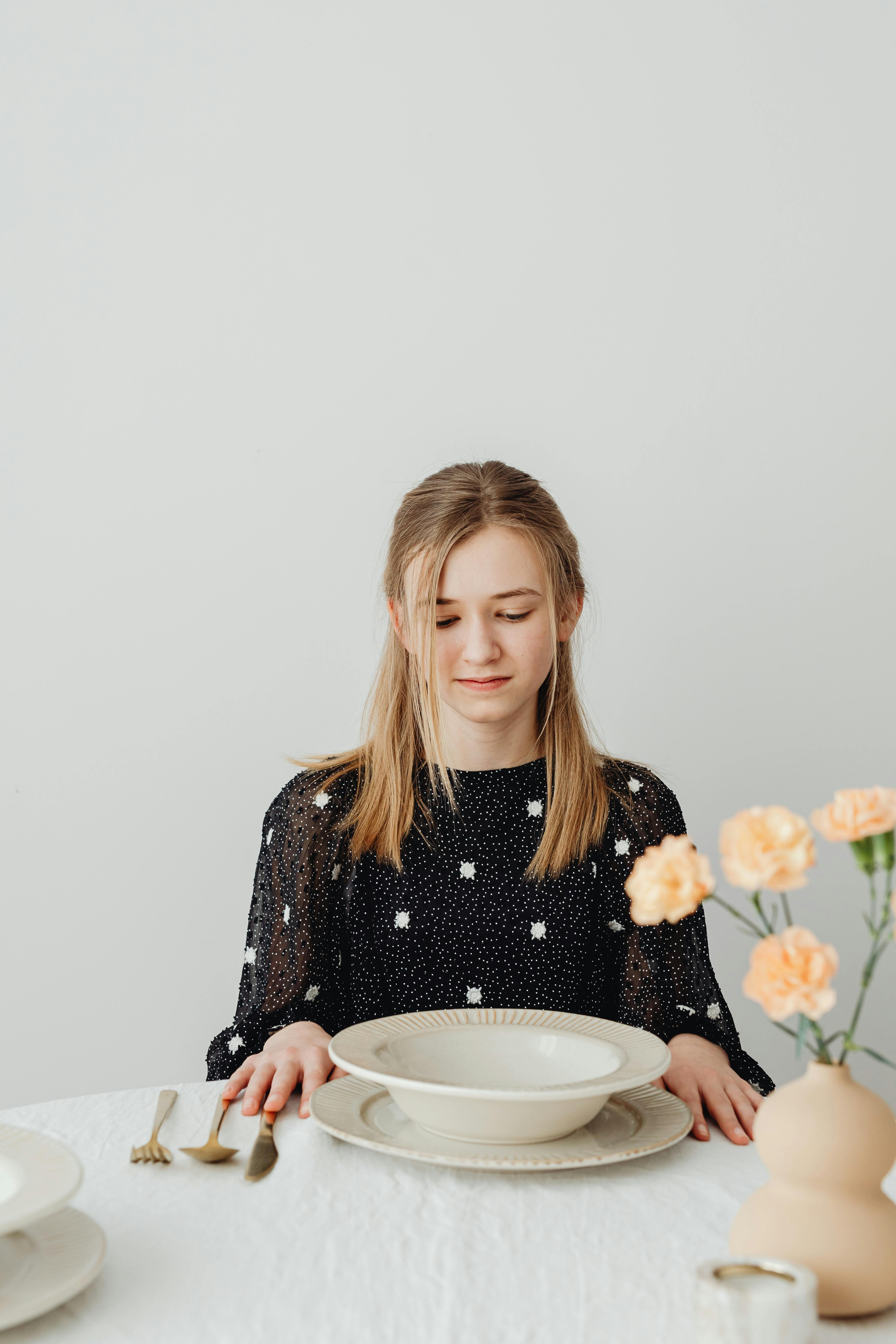 Girl Sitting at a Table Looking at her Plate · Free Stock Photo