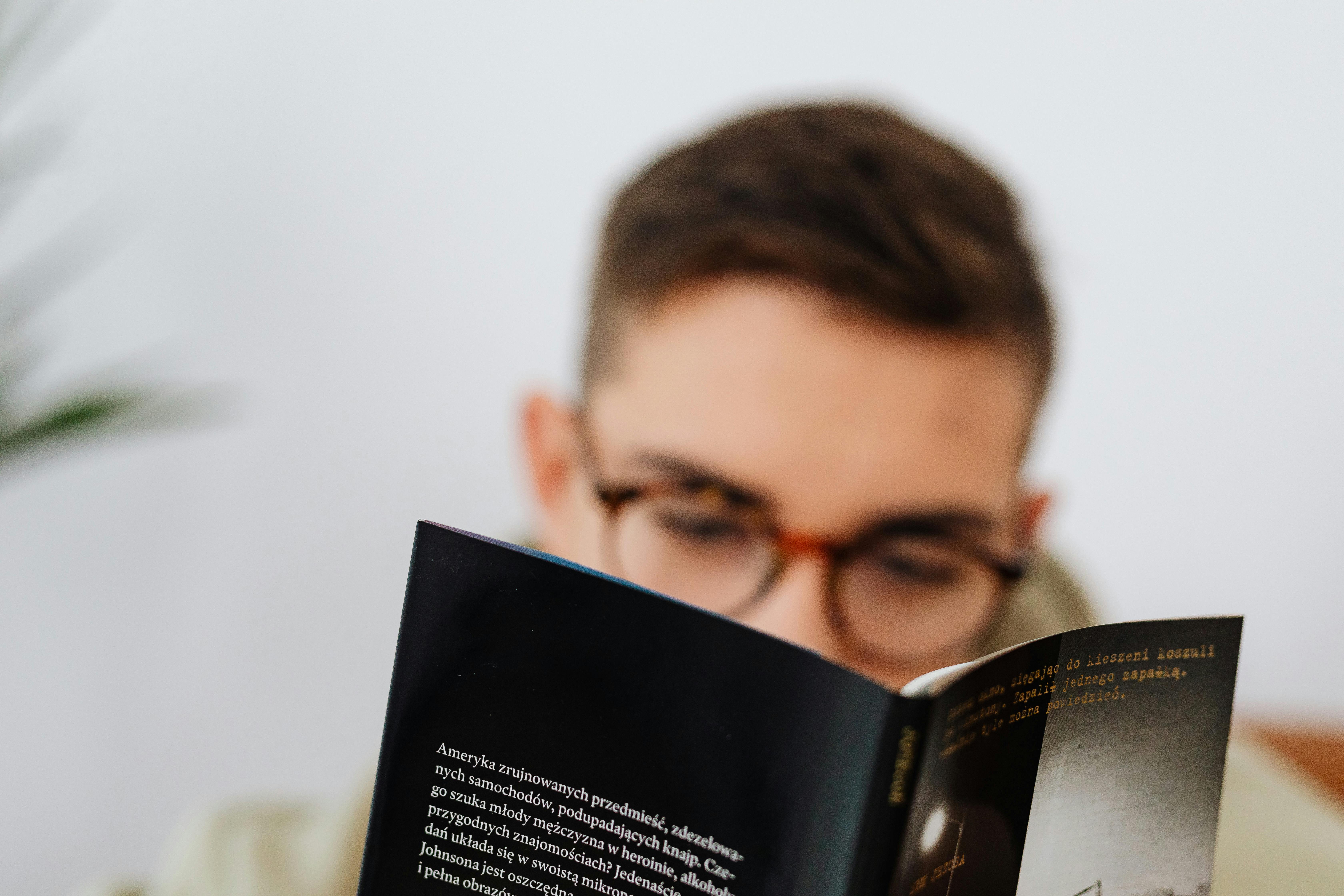 Close-Up Shot of a Man with Eyeglasses Reading a Book · Free Stock Photo