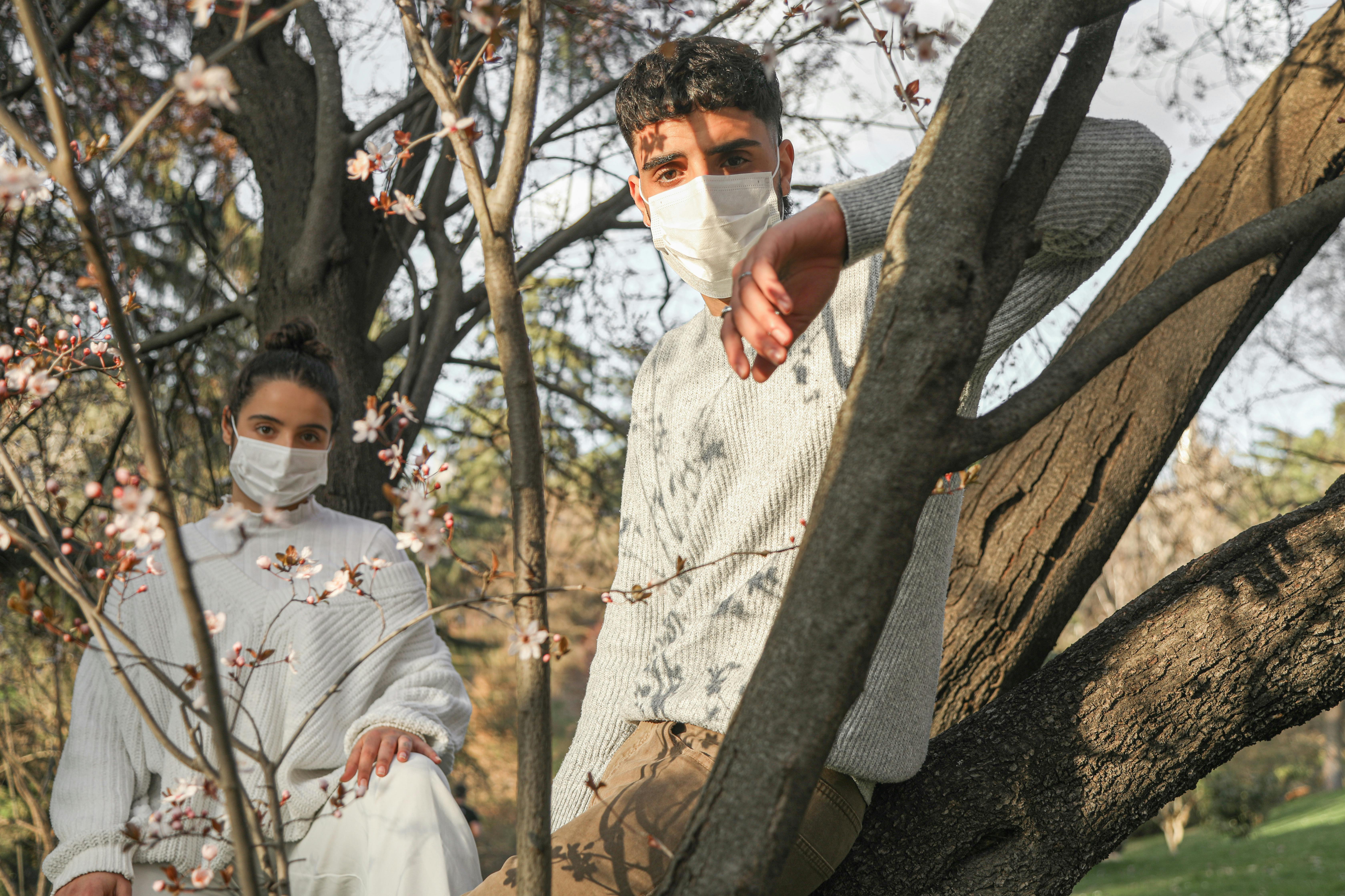 A Couple on a Tree Wearing Face Masks · Free Stock Photo