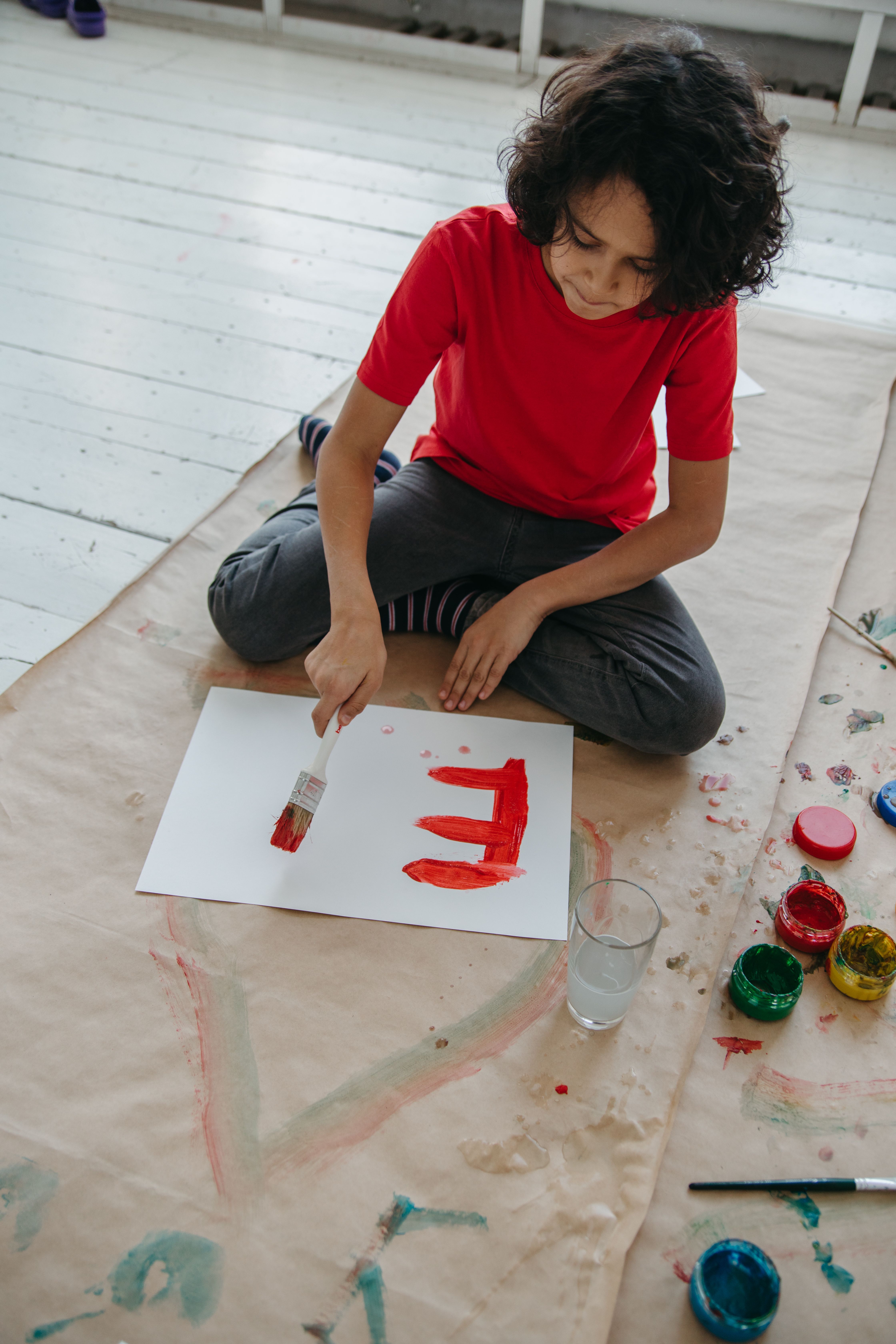 A Boy in Red Shirt Writing Letters on a Bond Paper Using Paintbrush ...