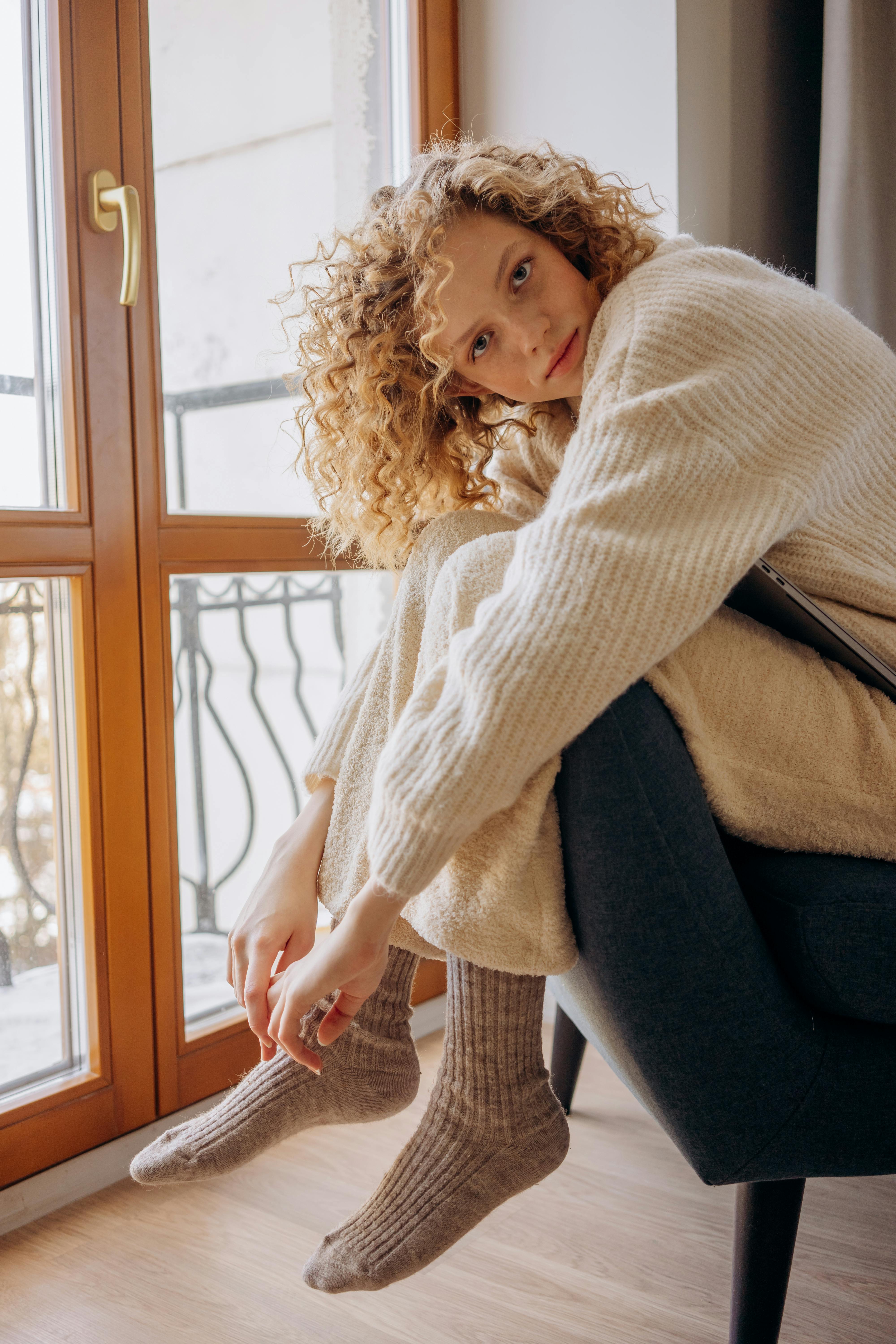 Woman in White Sweater Crouching on White Chair · Free Stock Photo