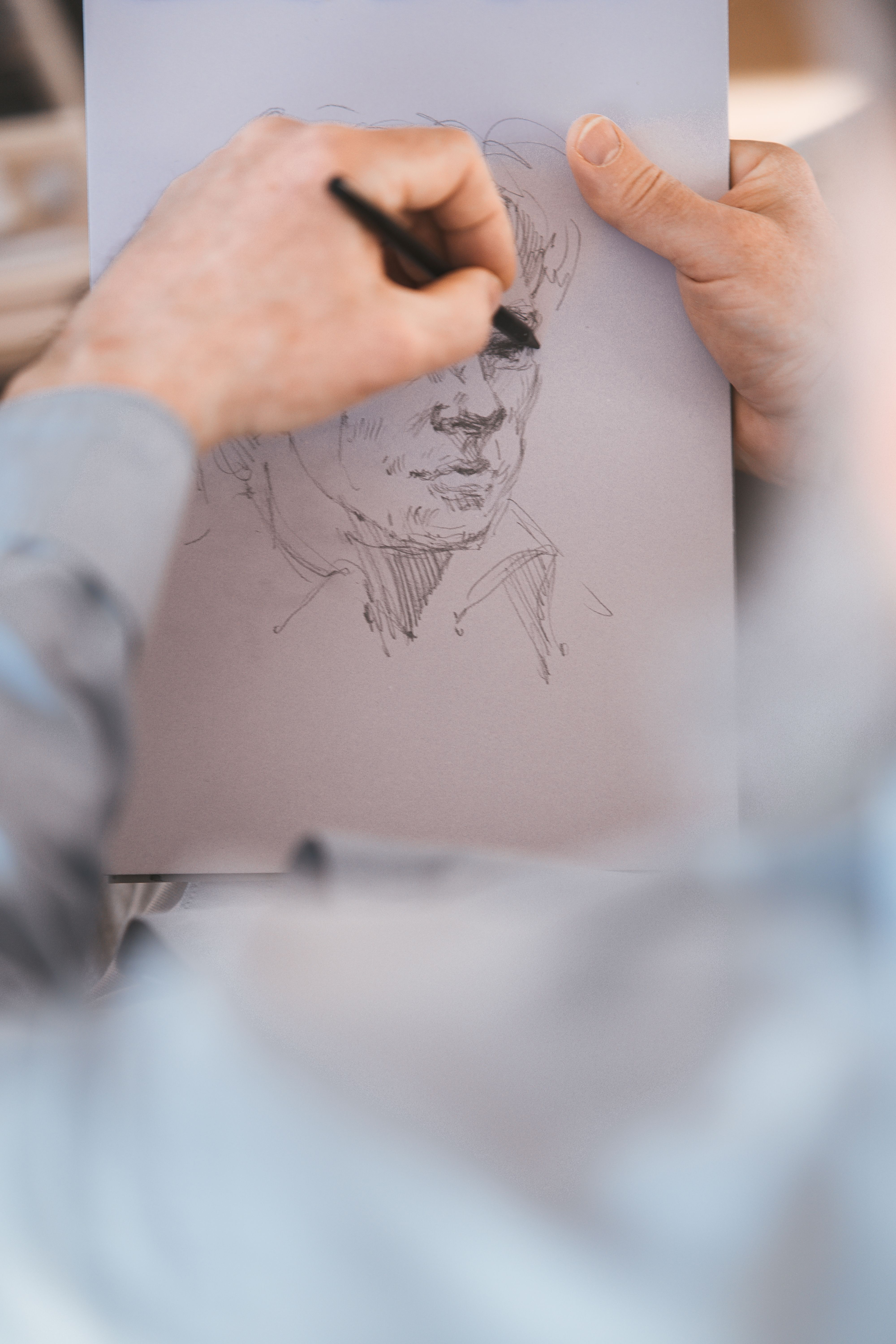 Close-up Shot of a Person in Gray Long Sleeves Drawing a Man on a Bond ...