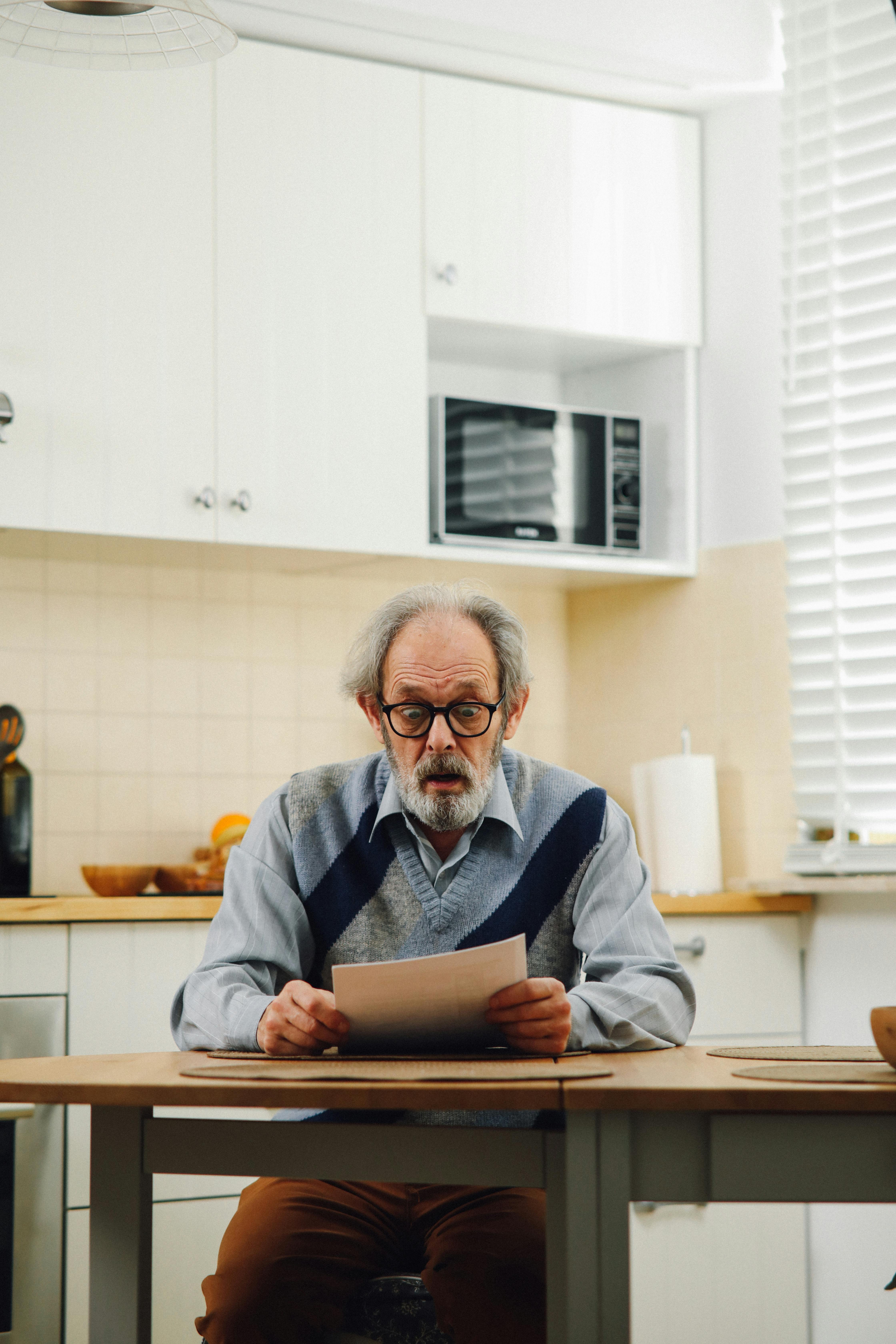 A Man Sitting at a Table with a Piece of Paper · Free Stock Photo