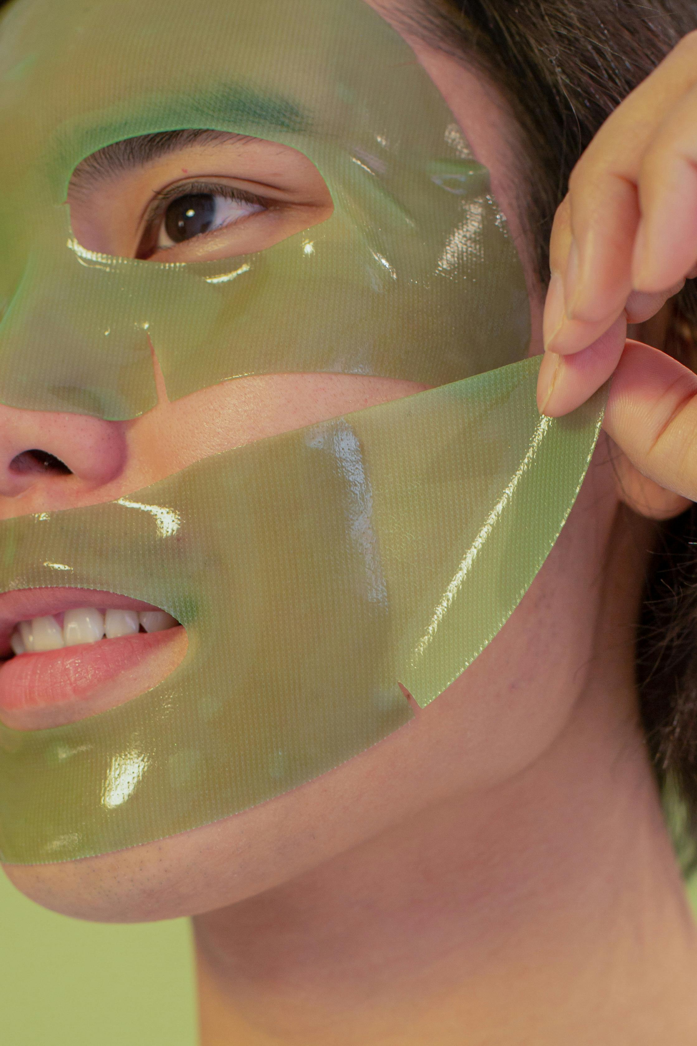 Crop Asian man removing sheet mask from face · Free Stock Photo