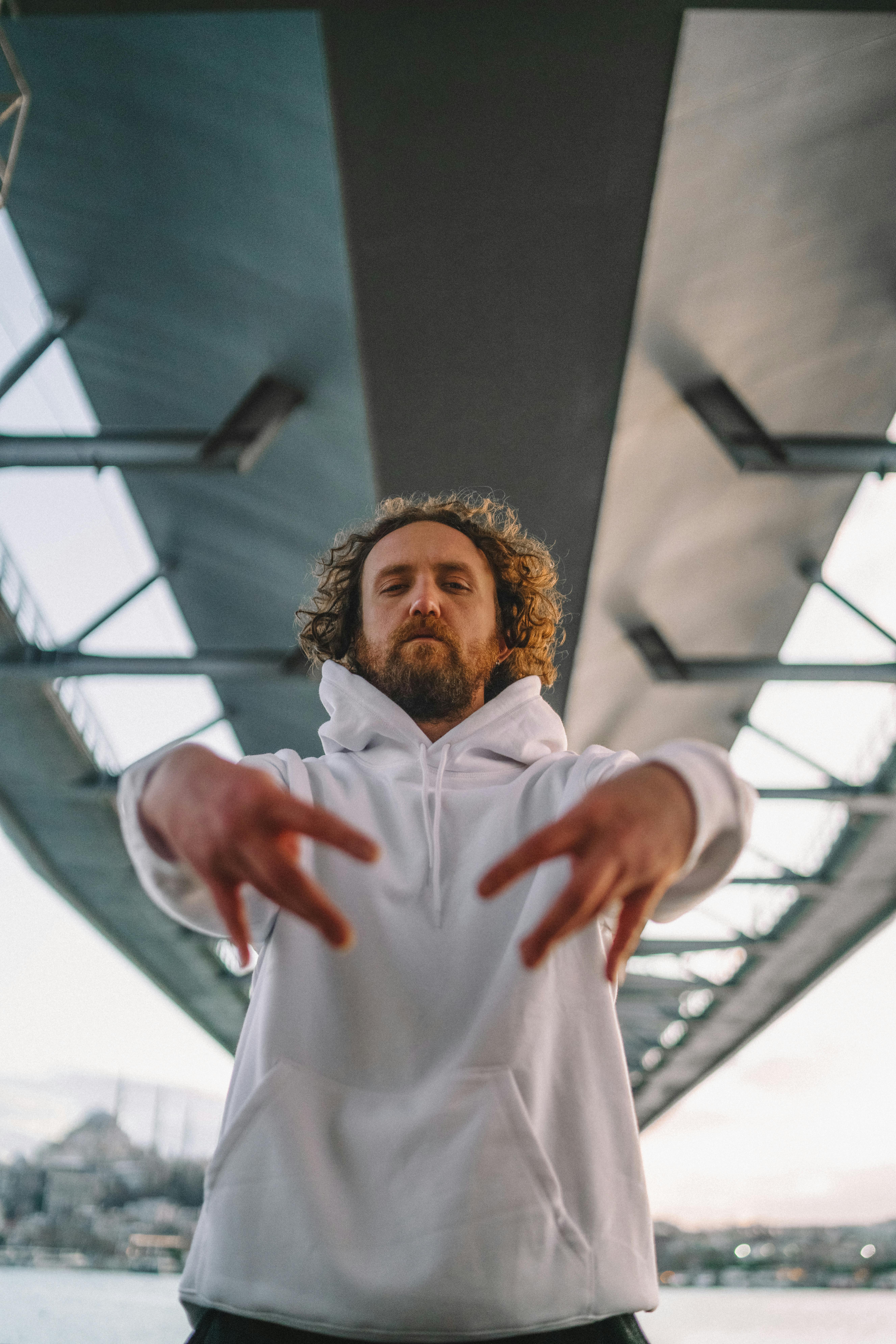 Male near river under bridge with fingers crossed · Free Stock Photo
